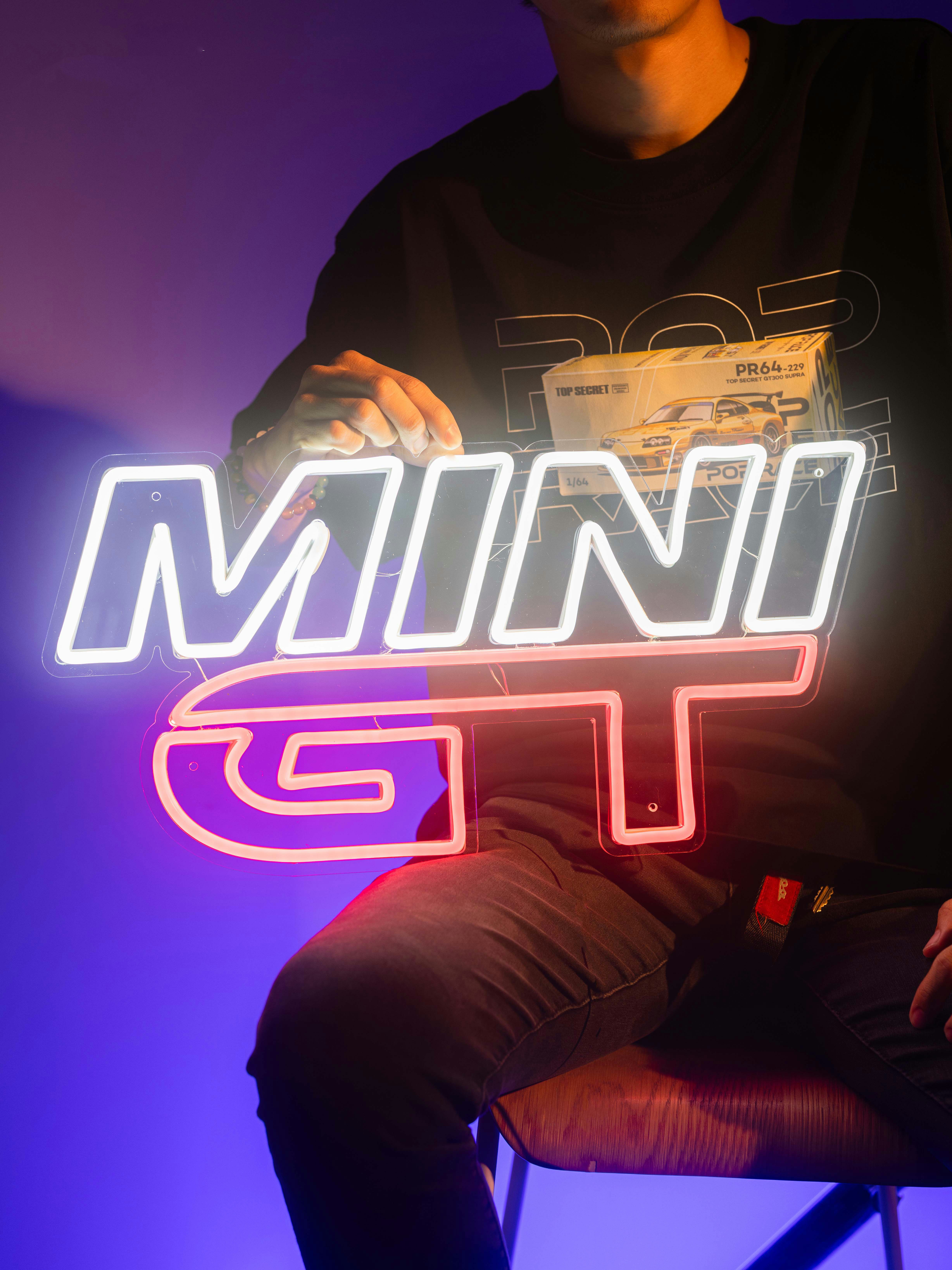 A person holds a "mini gt" neon sign. photo – Free Colorful Image on ...