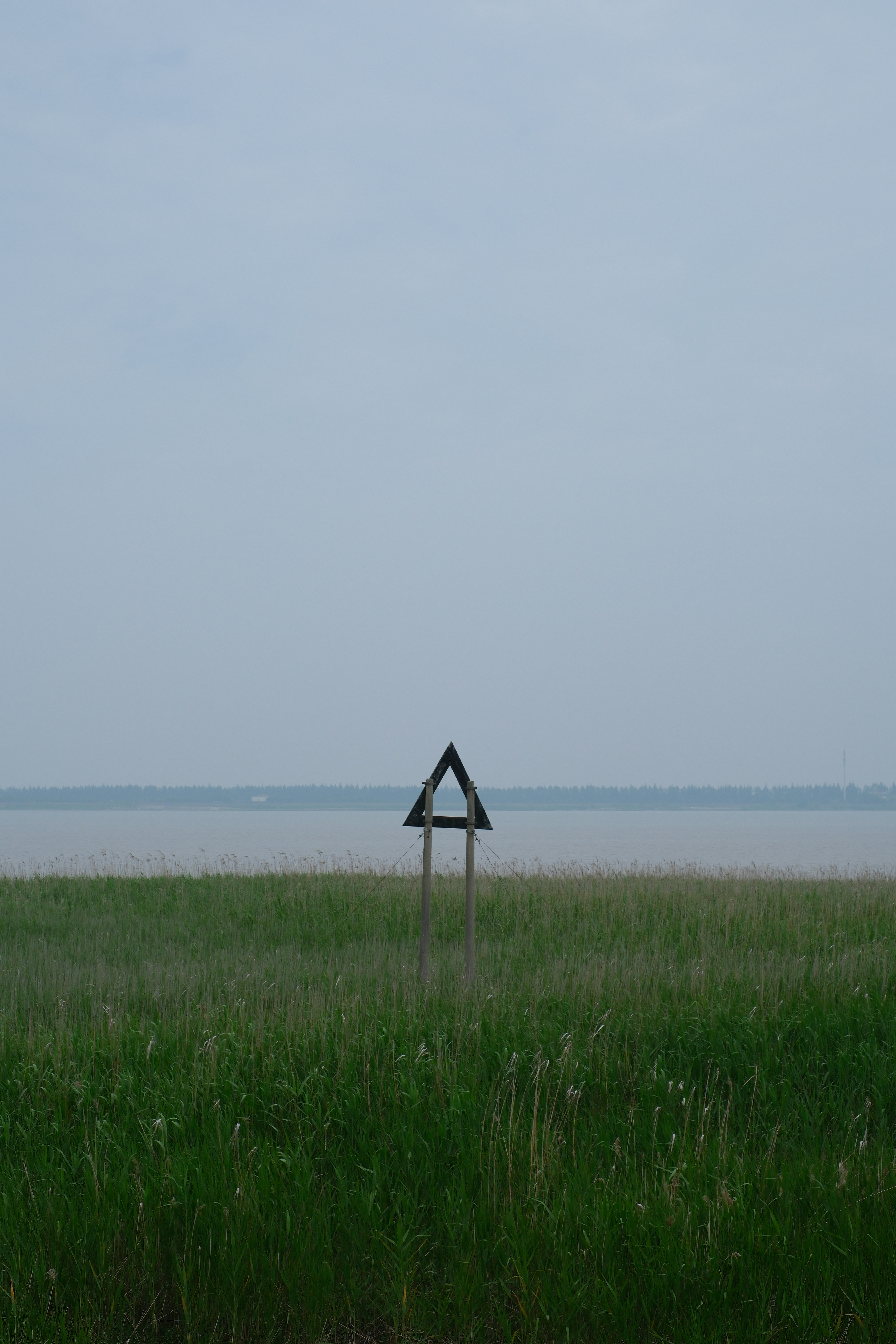 A triangle sign stands in a grassy field. photo – Free Beach Image on ...