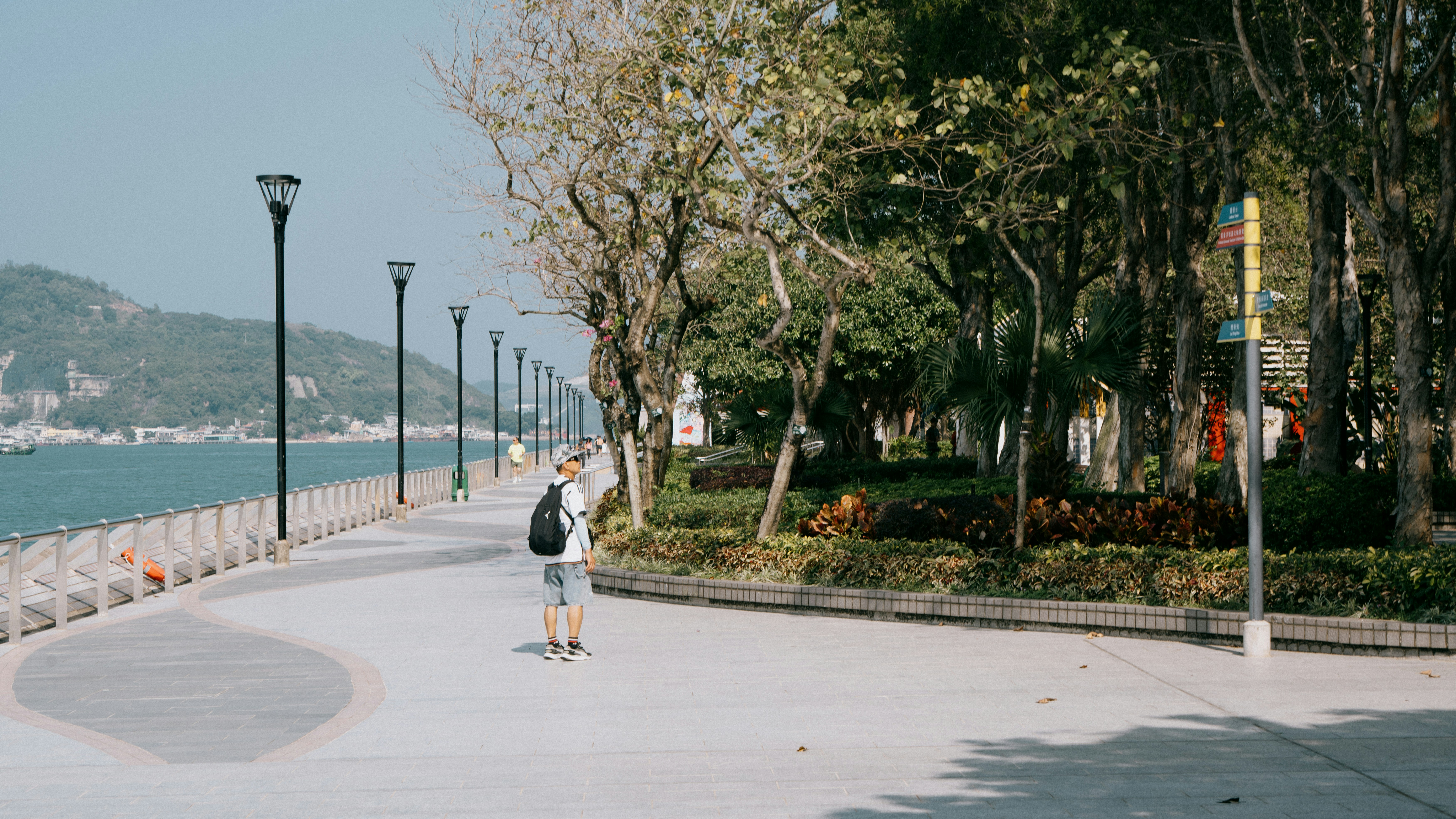 Person walks along a waterfront path in a park. photo – Free Hong kong ...