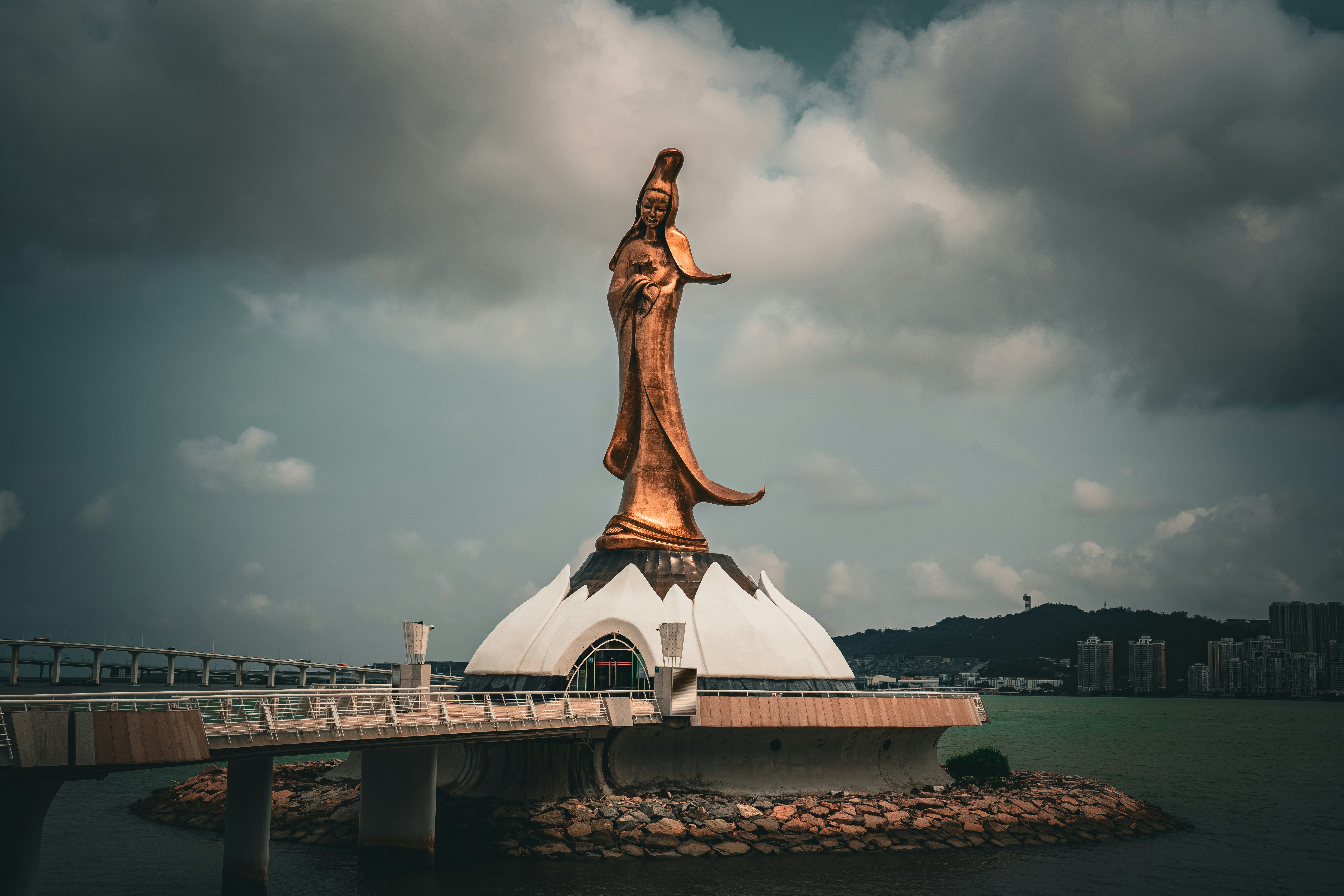 A golden goddess statue stands tall near the water. photo – Free Woman ...