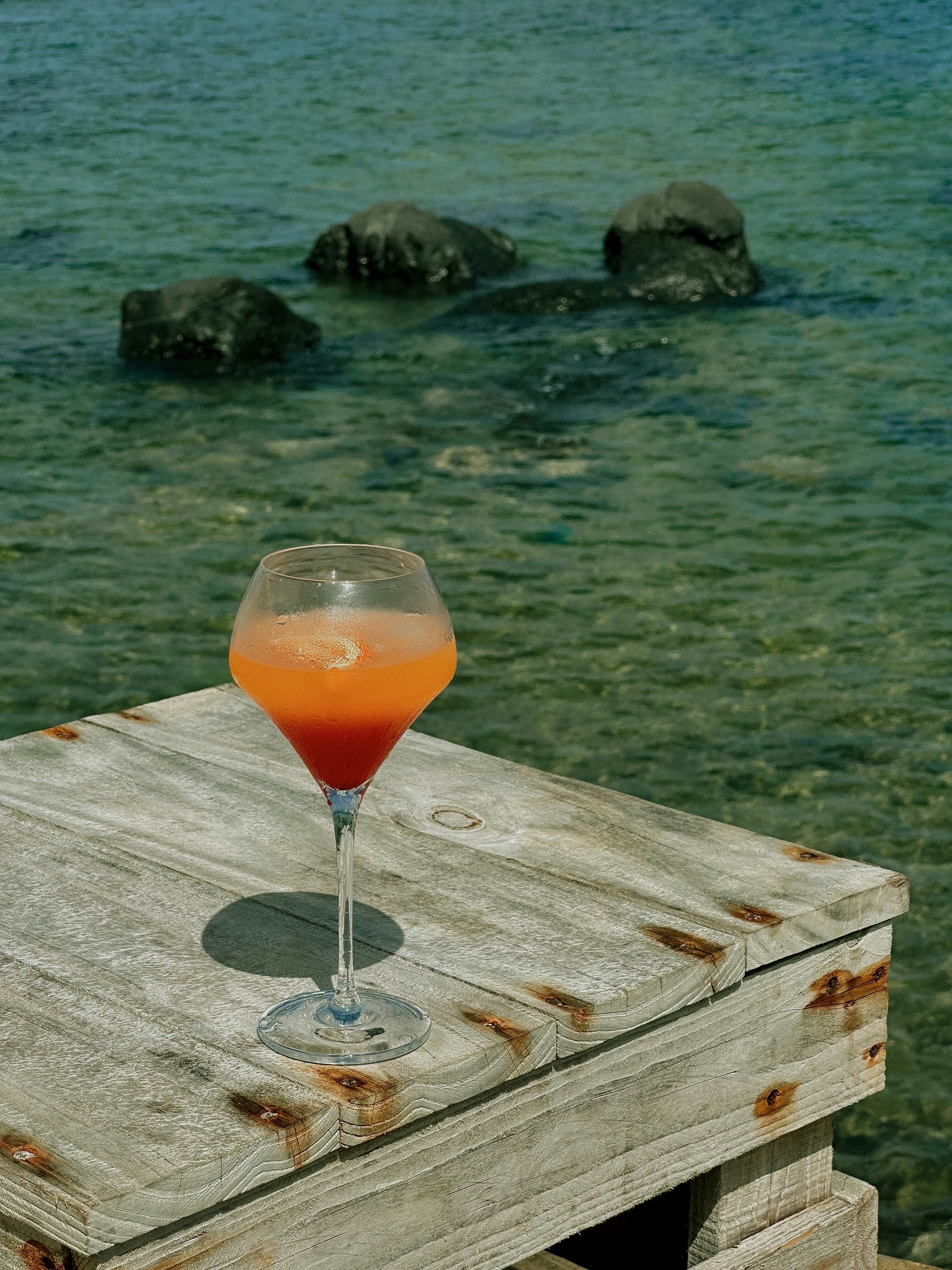 Orange Elixir on a Weathered Pier Above Turquoise Waters