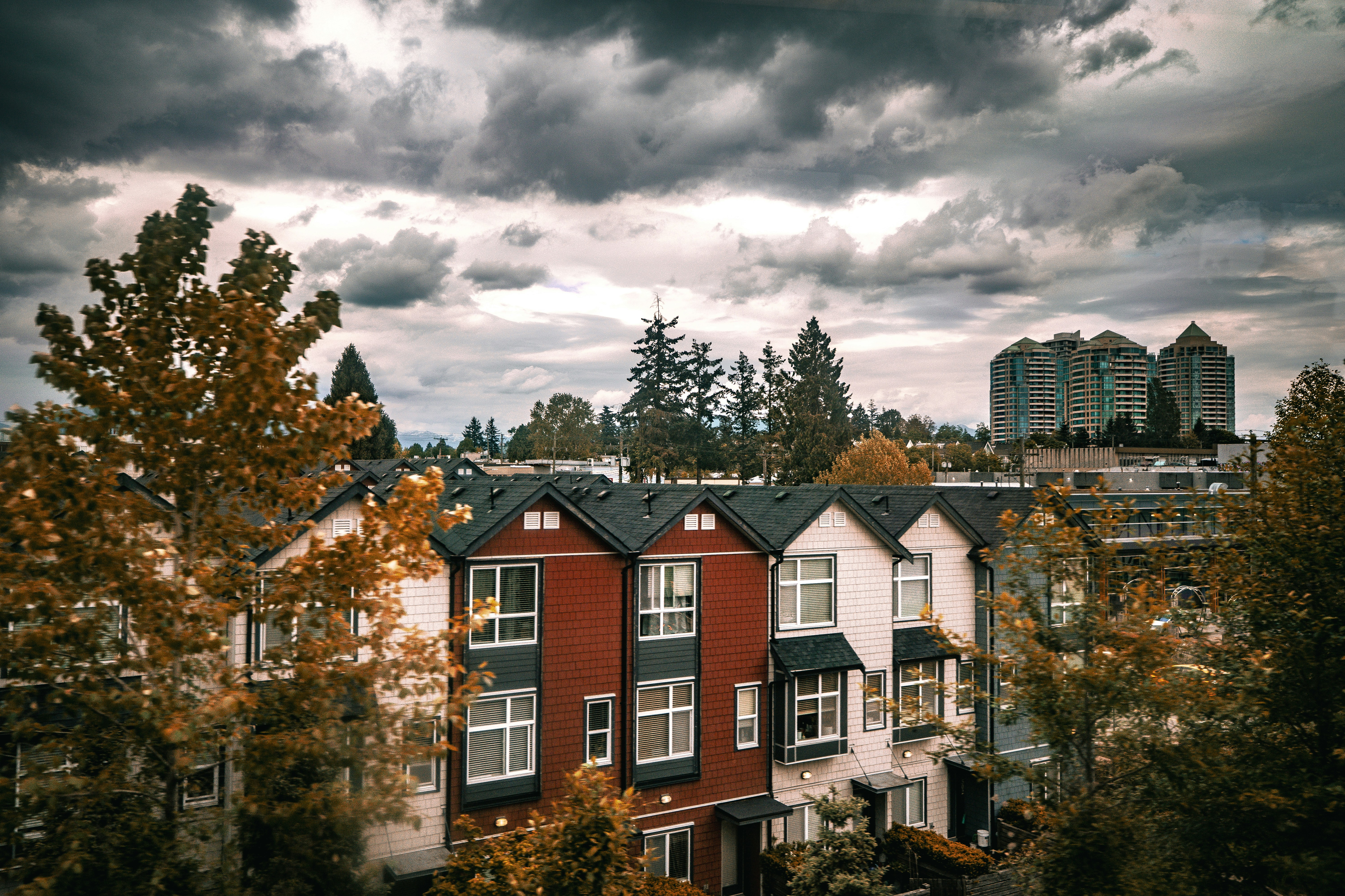 Townhomes sit beneath a cloudy autumn sky.