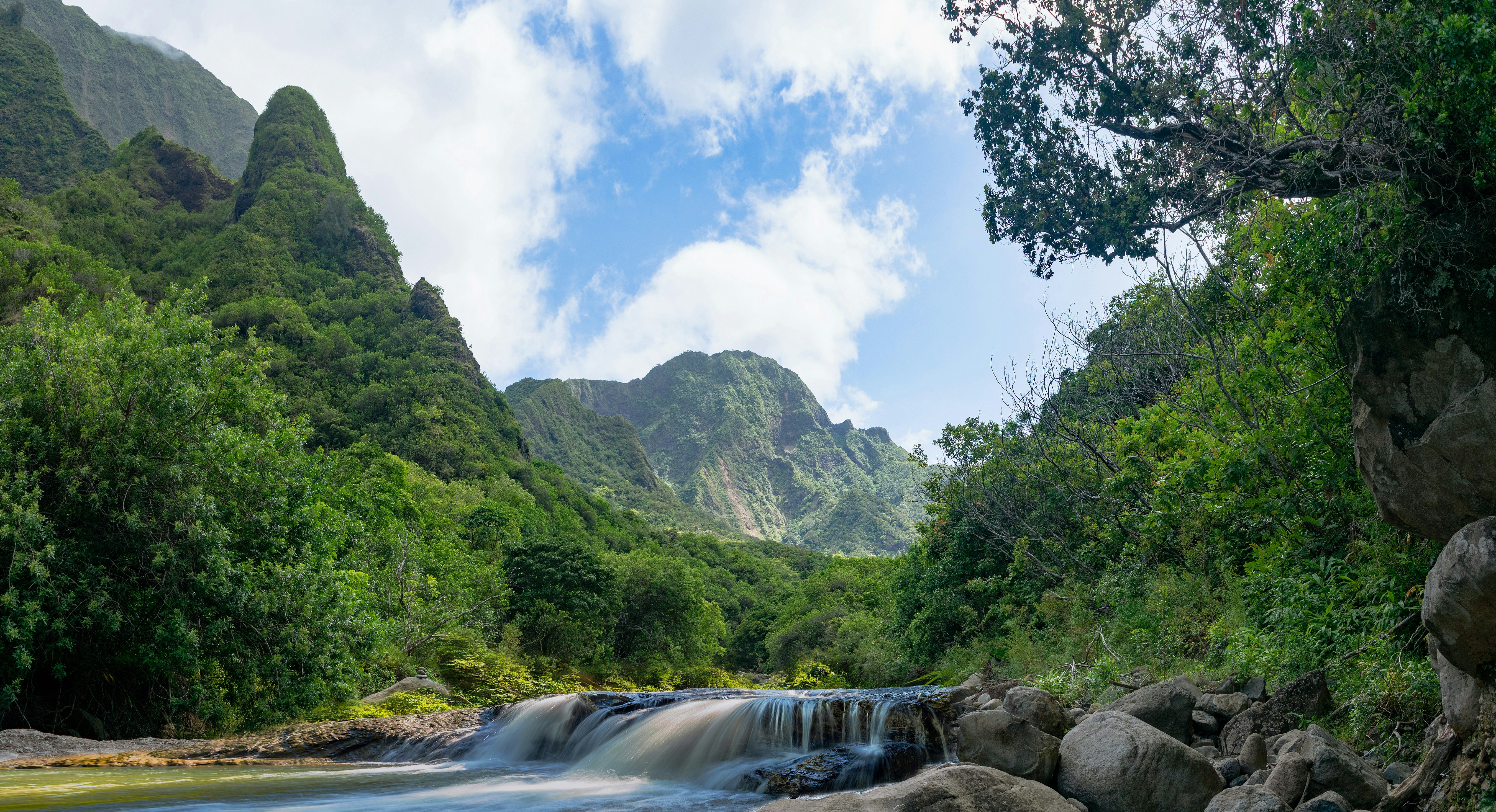 Mountains and lush greenery overlook a small waterfall. photo – Free ...