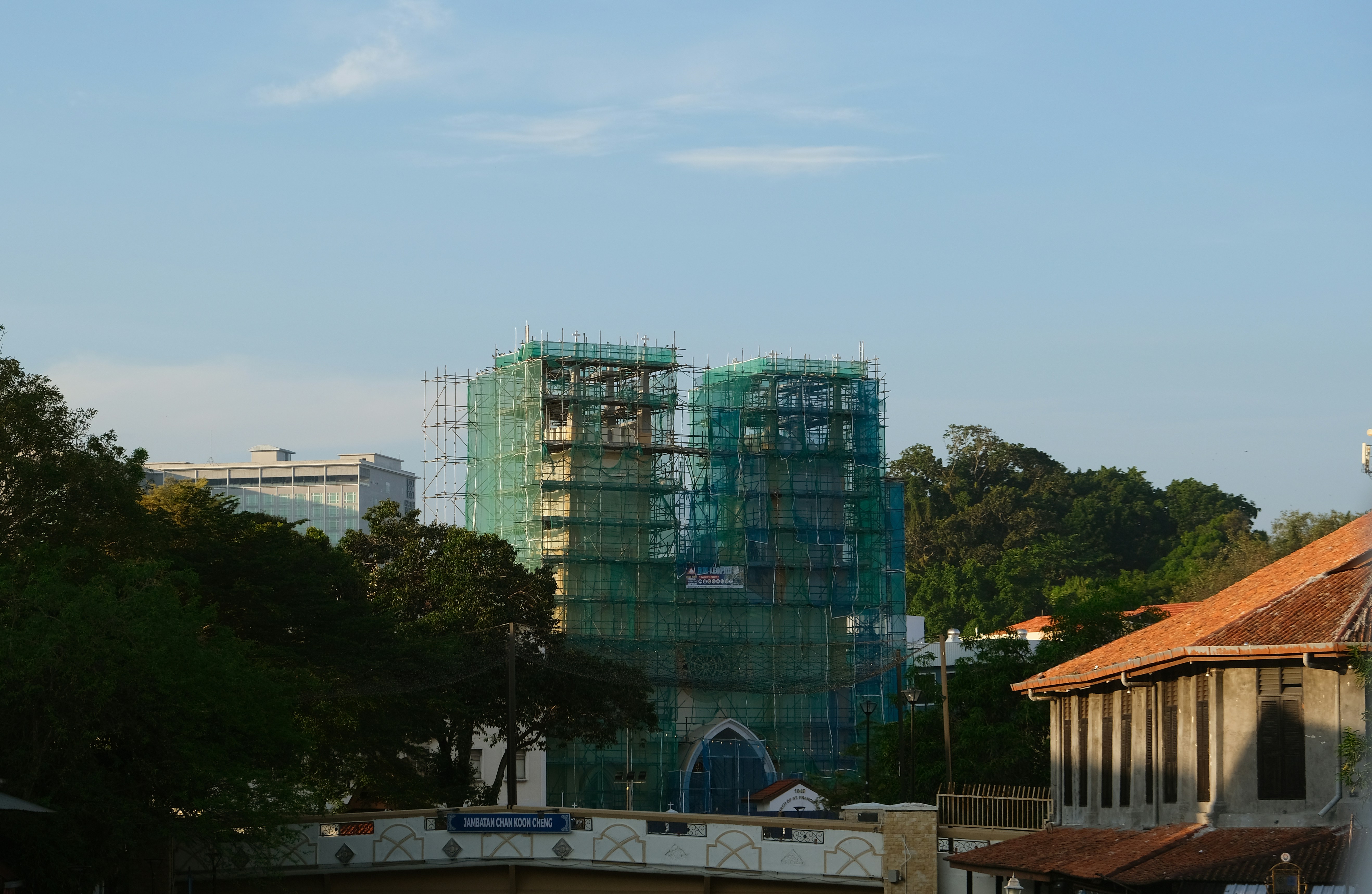 Construction site wrapped in scaffolding, showcasing a blend of urban architecture and nature. The scene captures the ongoing transformation of the city landscape.