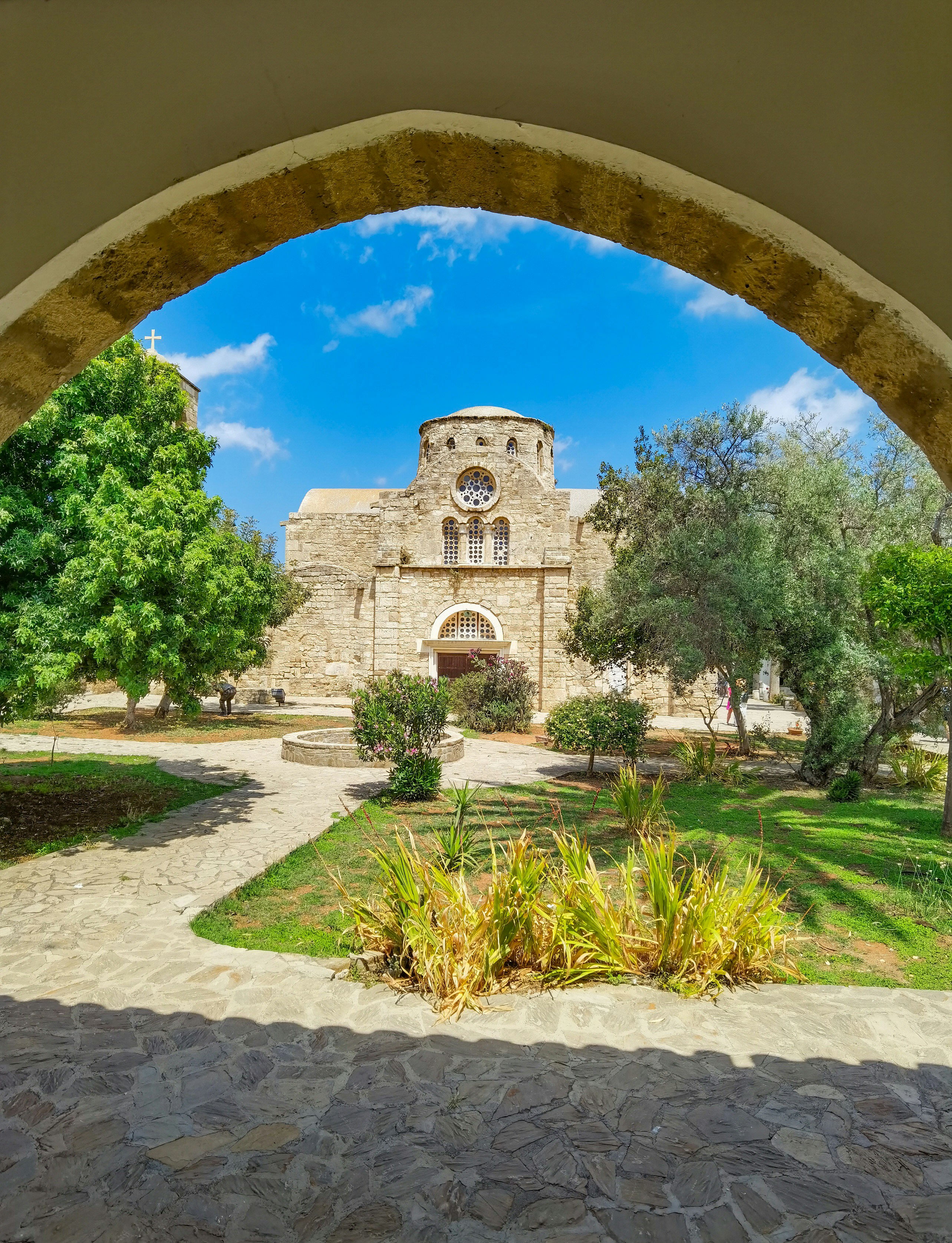 An ancient church framed by an archway and trees.