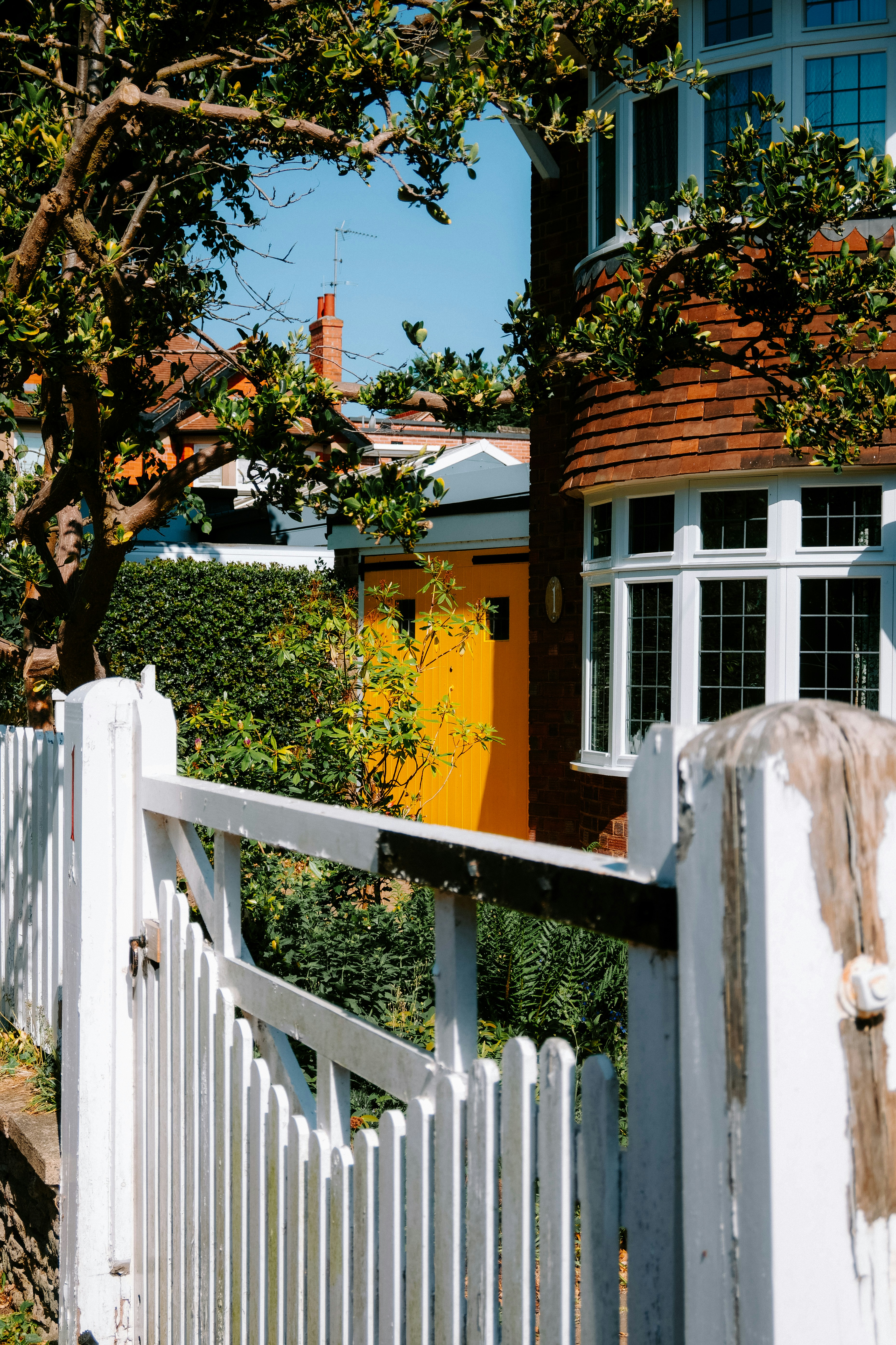 A white gate frames a house and colorful buildings. photo – Free ...