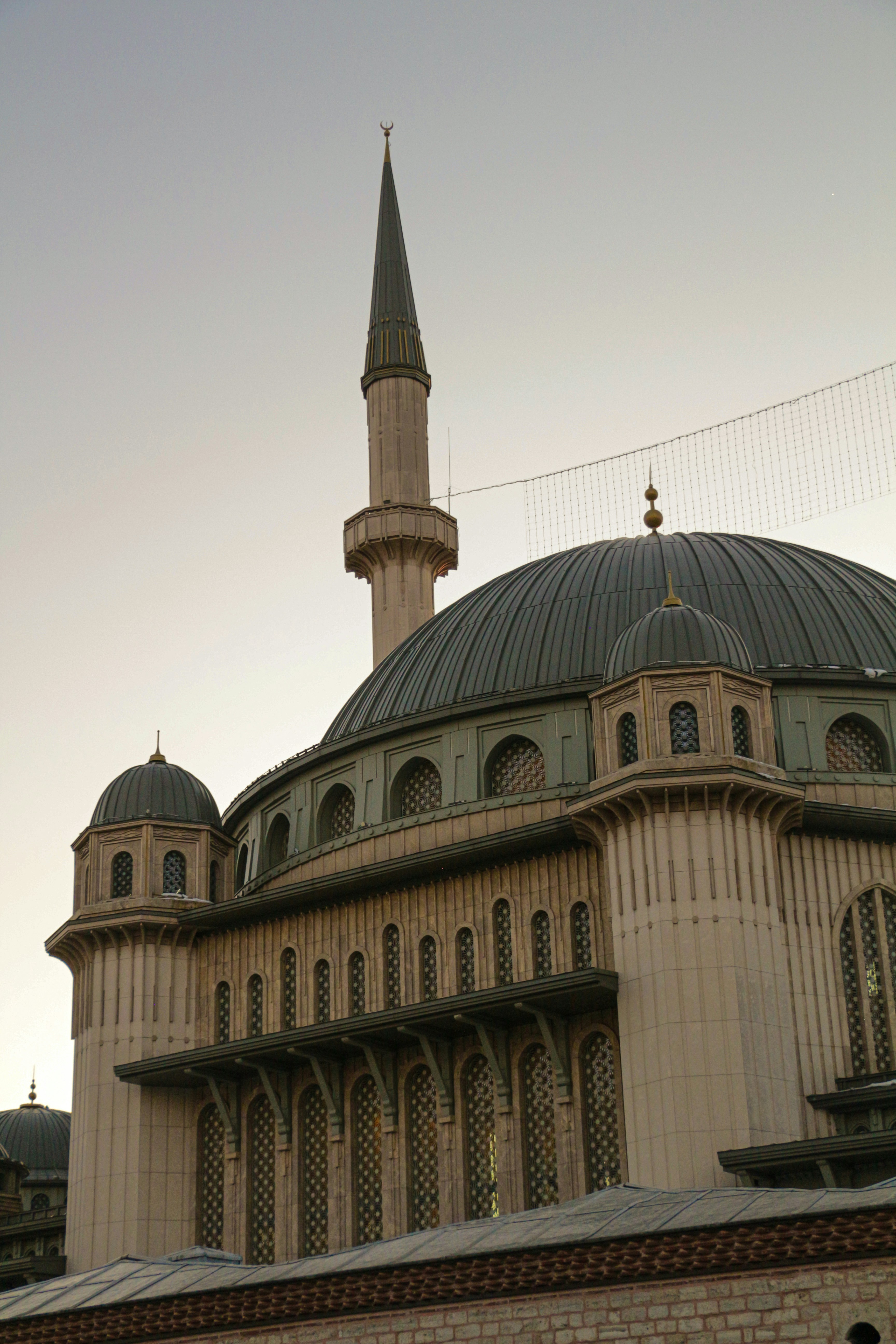 Detailed view of an Ottoman-style mosque showcasing its intricate dome and minaret against a soft evening sky.