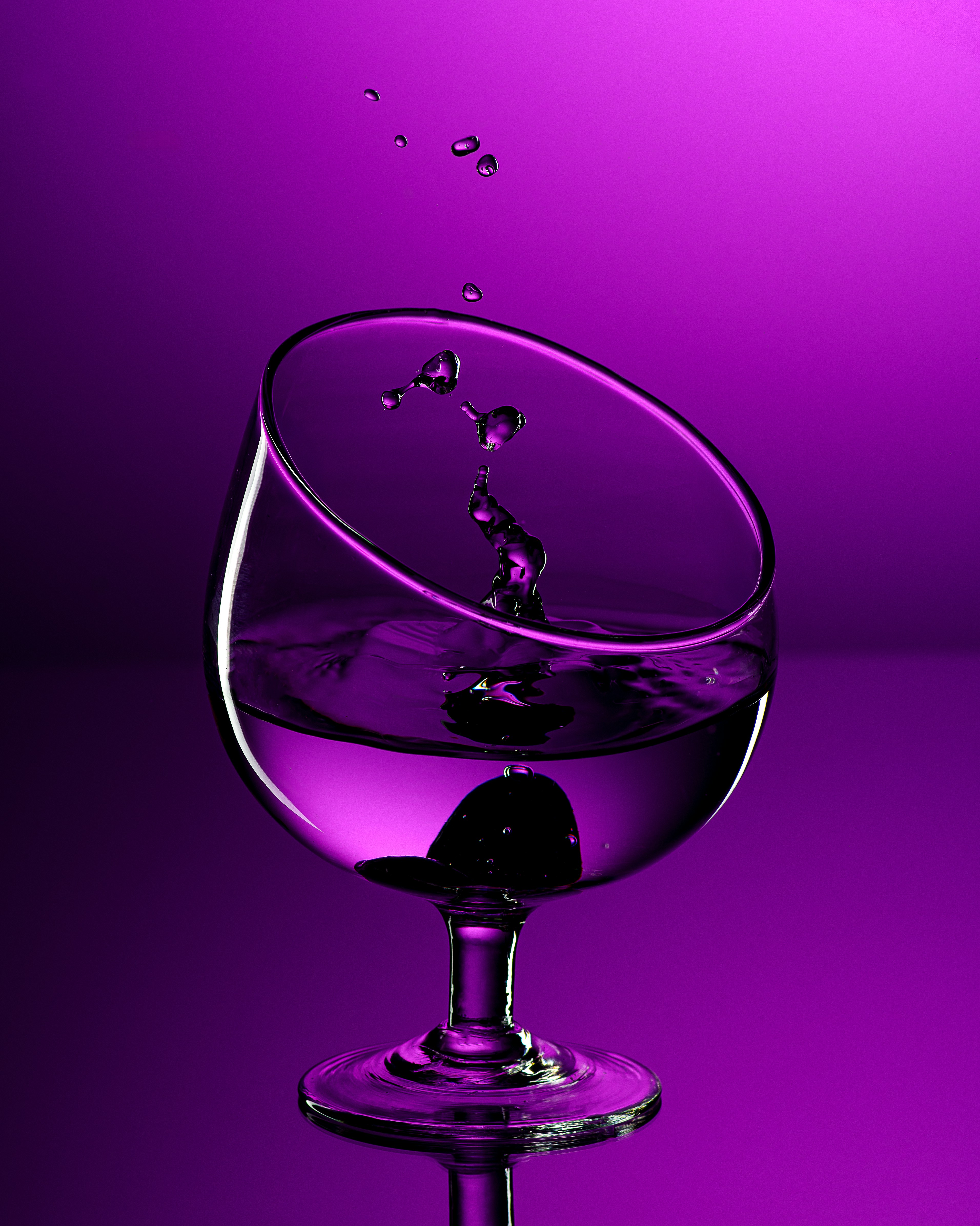 El agua salpica dramáticamente dentro de un vaso morado. foto – Imagen ...