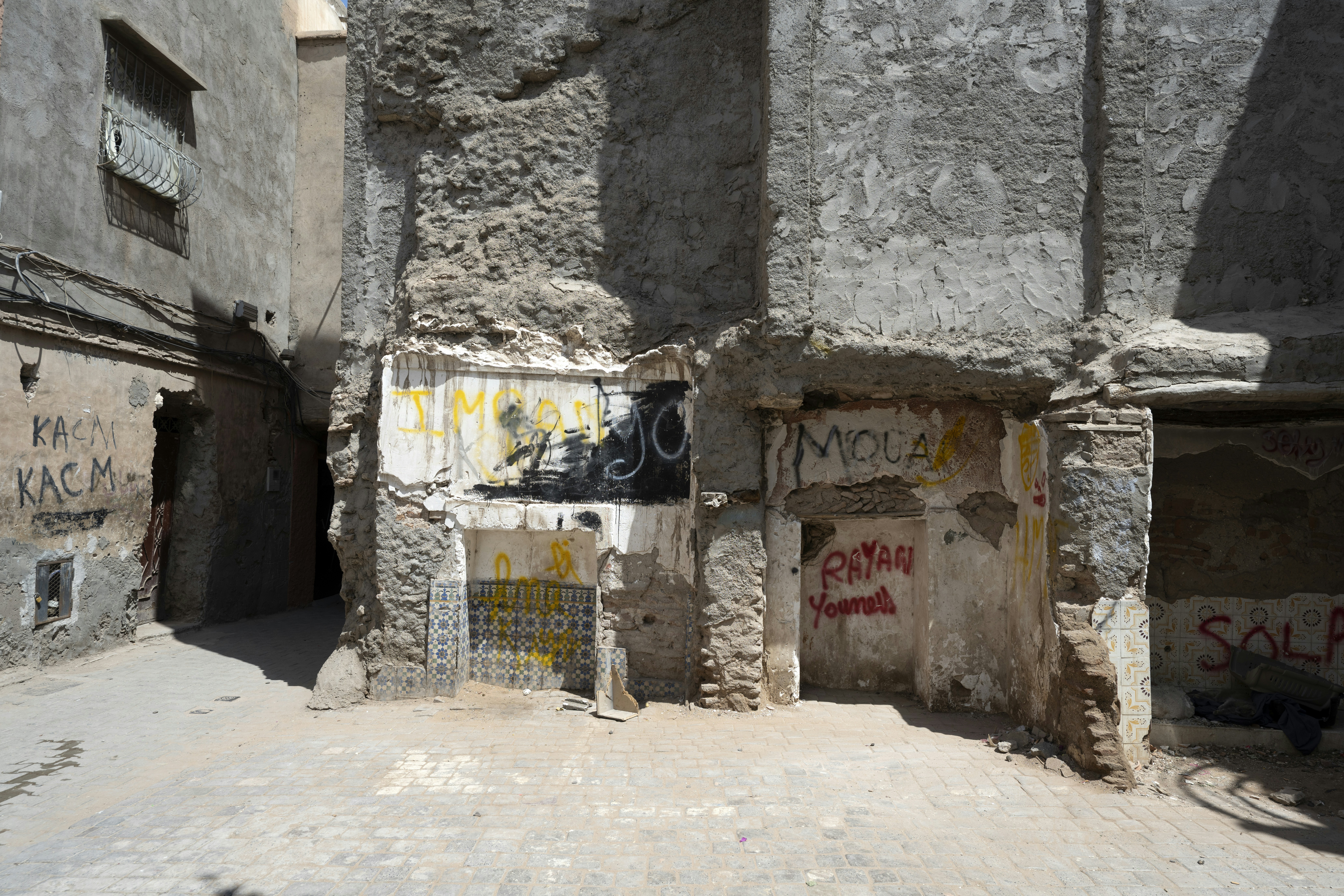 Weathered walls adorned with graffiti in a narrow alleyway, showcasing the contrast between urban art and crumbling architecture.