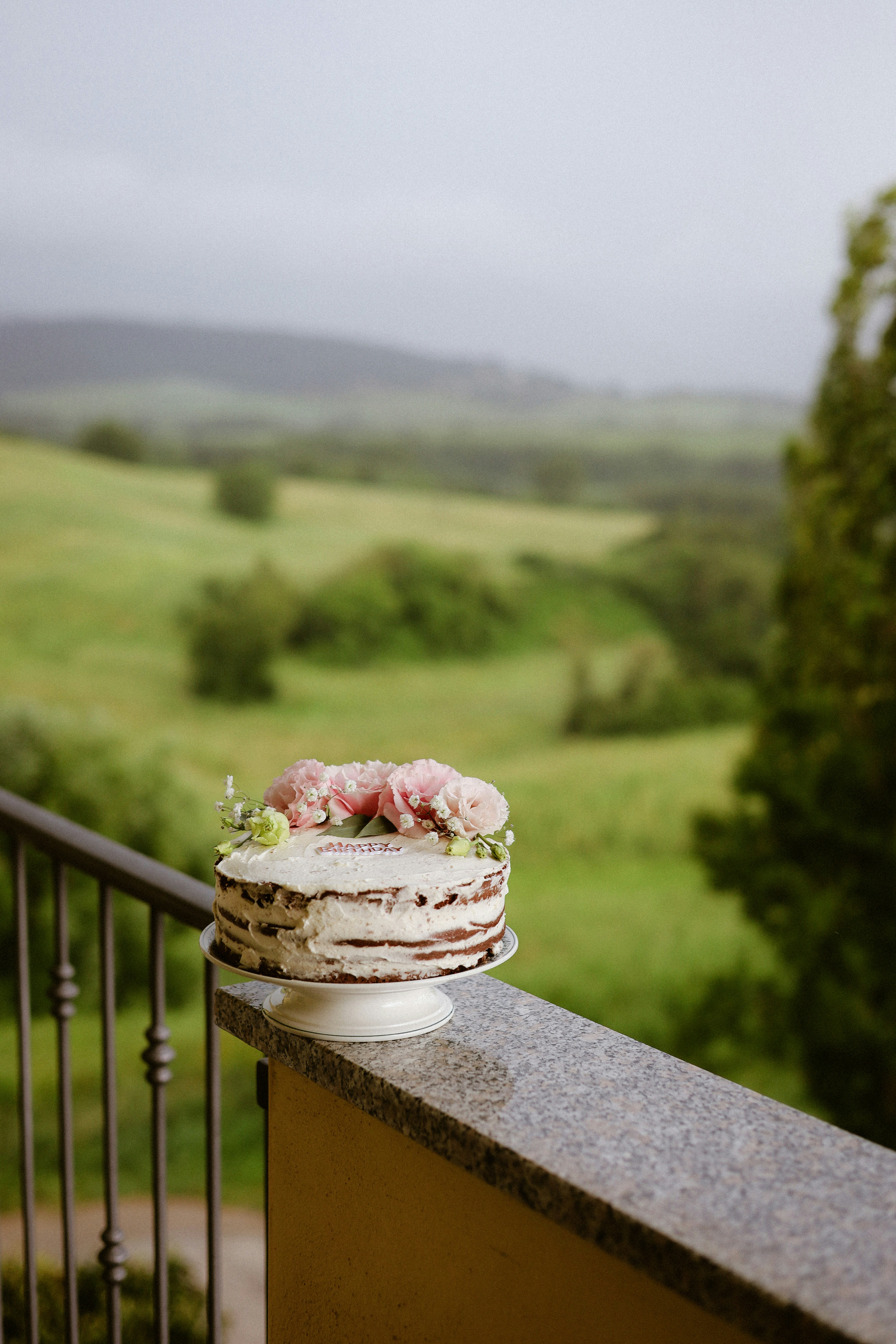 Pastel Naked Cake on a Stone Balcony Framed by Rolling Green Hills