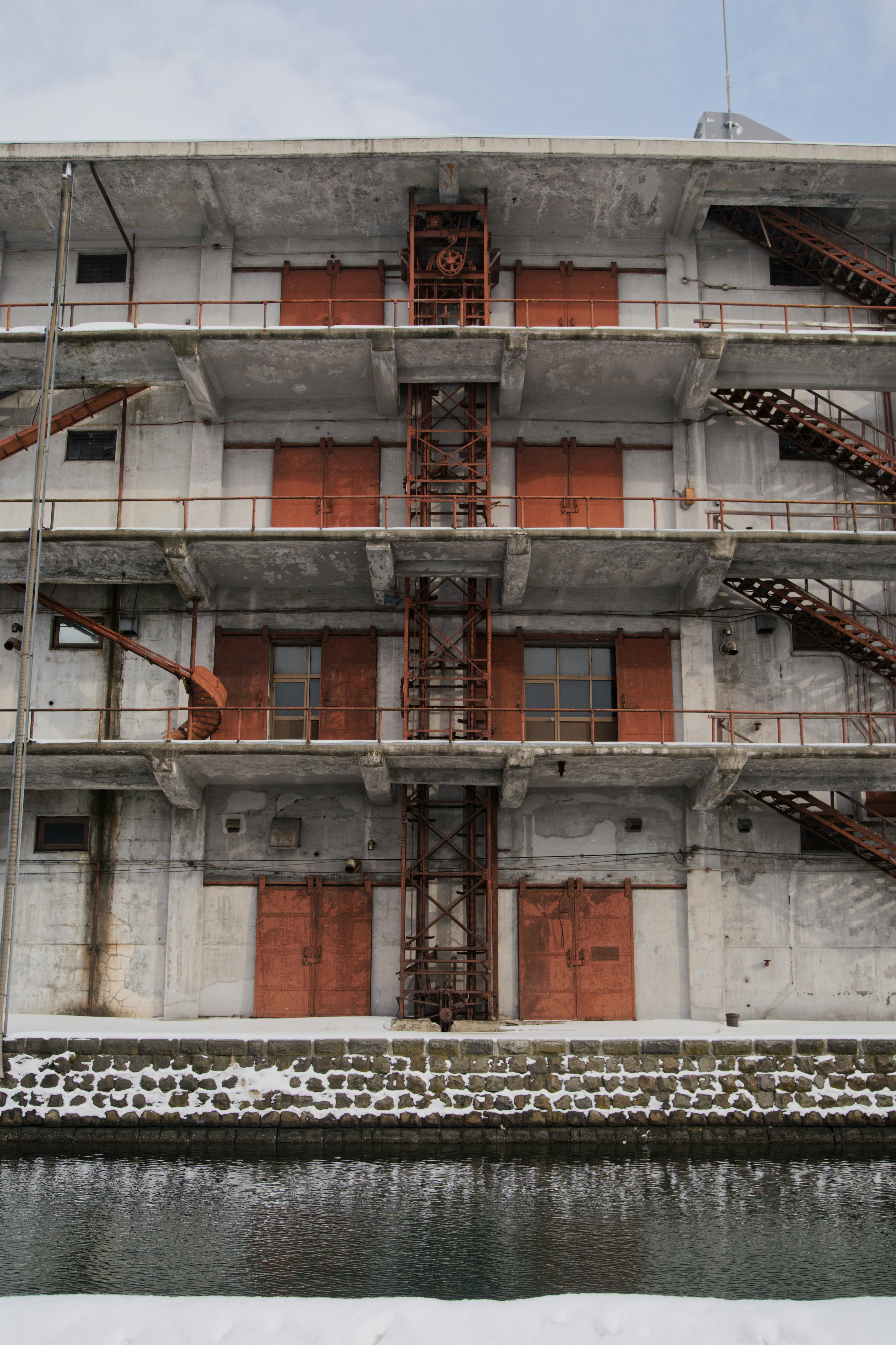 Abandoned Waterfront Factory Facade with Rusted Elevator Core