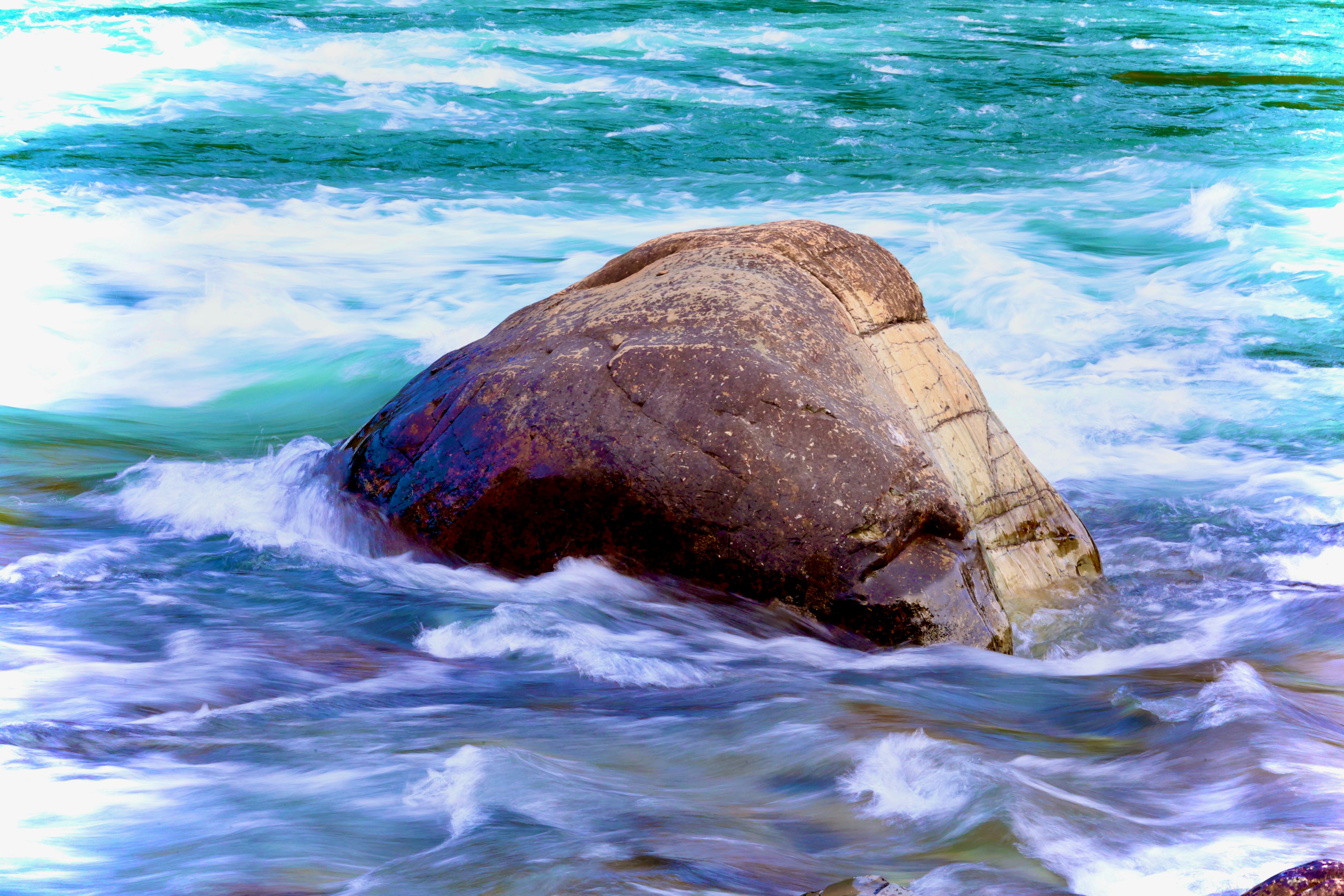 Water rushes around a large, submerged rock. photo – Free Beach Image ...
