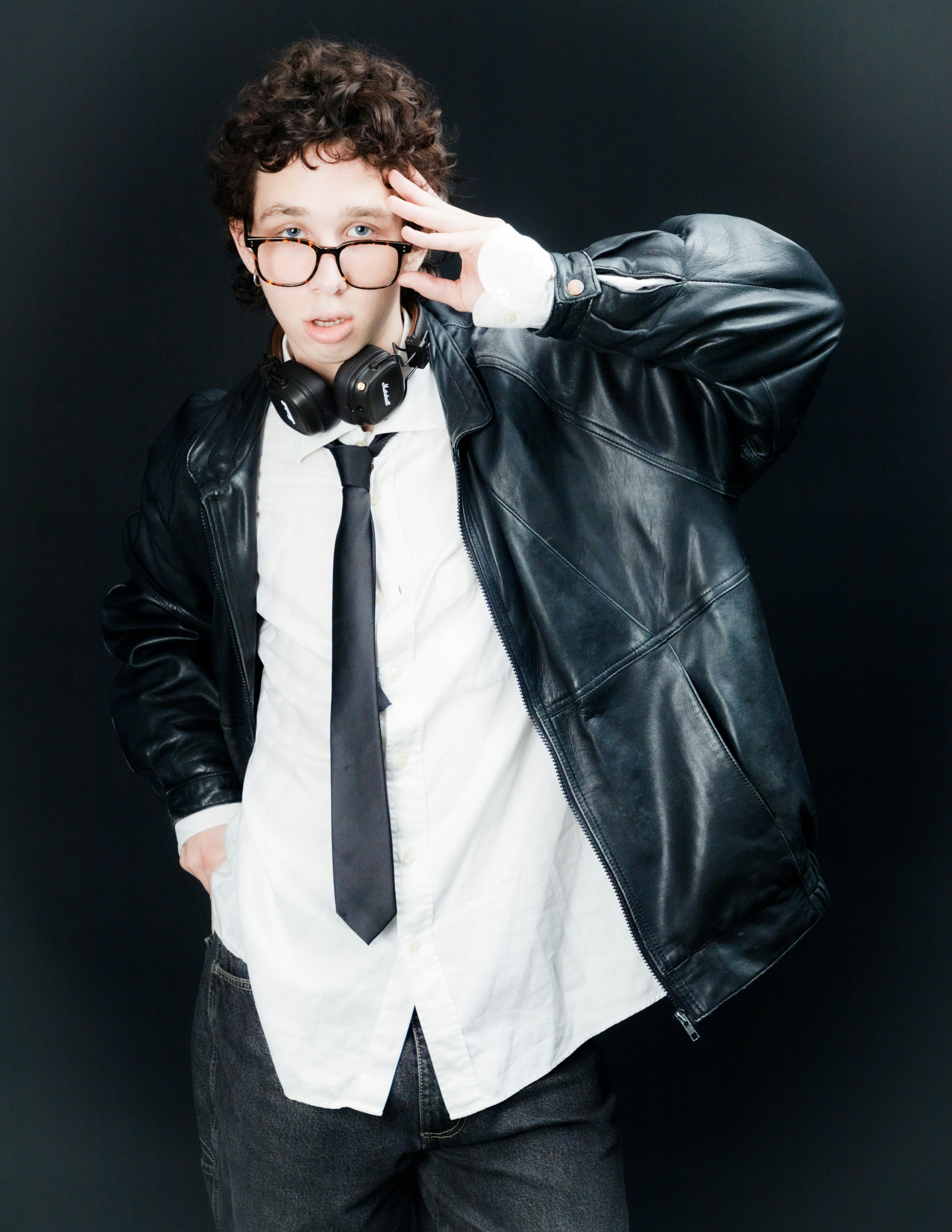 A young person poses in a leather jacket.