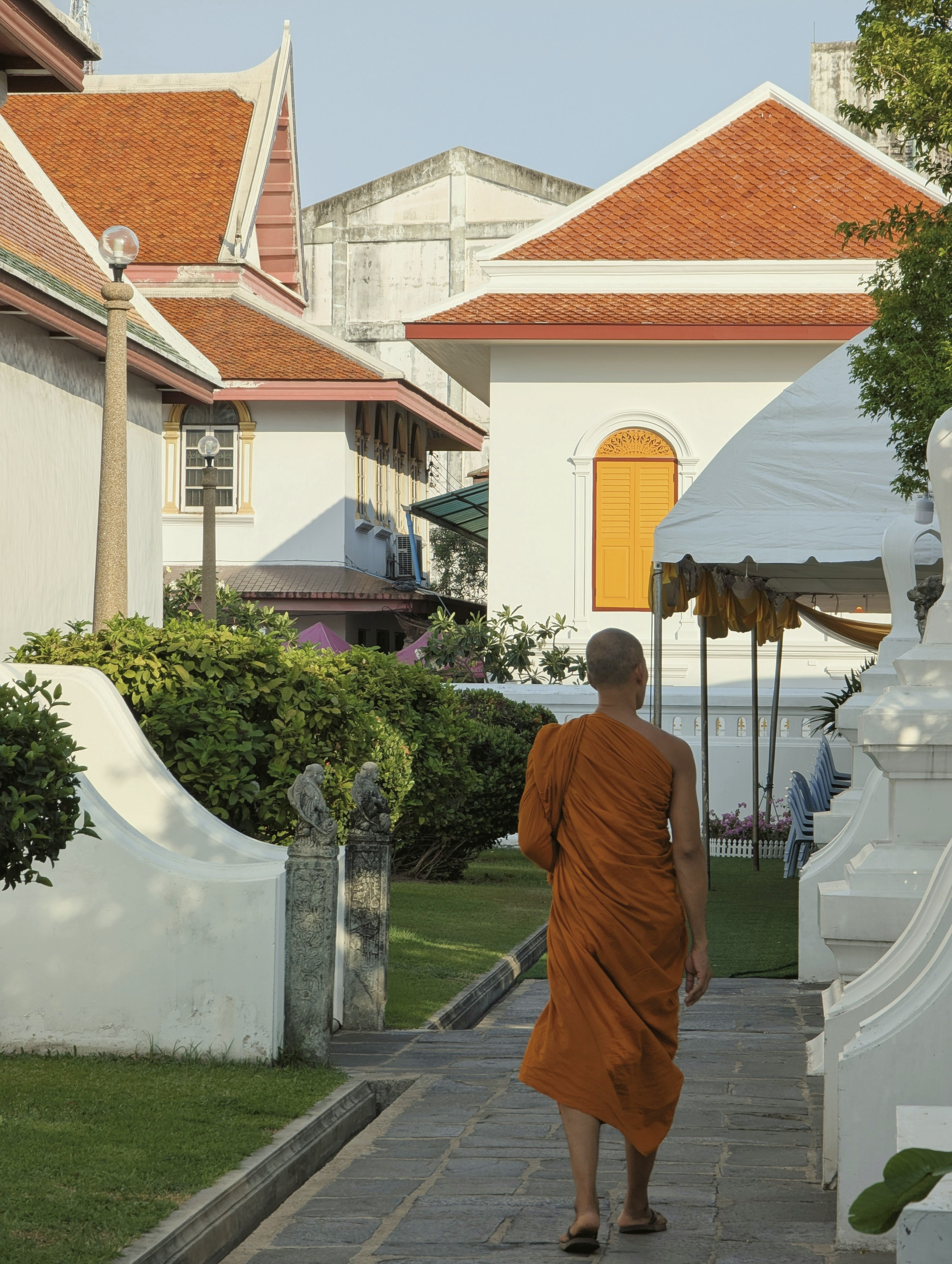 A monk walks along a path near temple buildings. photo – Free Thailand ...