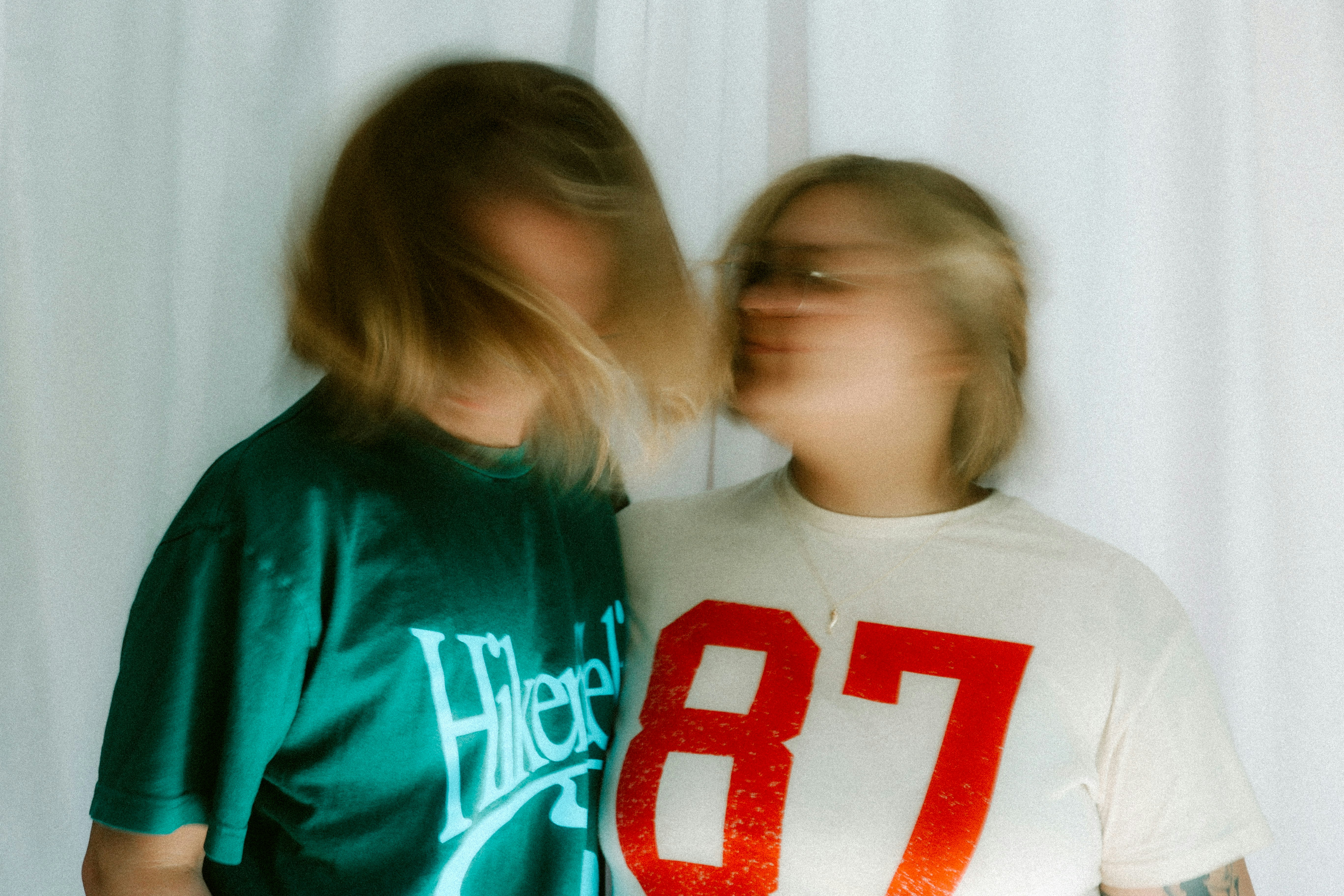 Two friends sharing a moment, their movements creating a dynamic blur against a soft backdrop.
