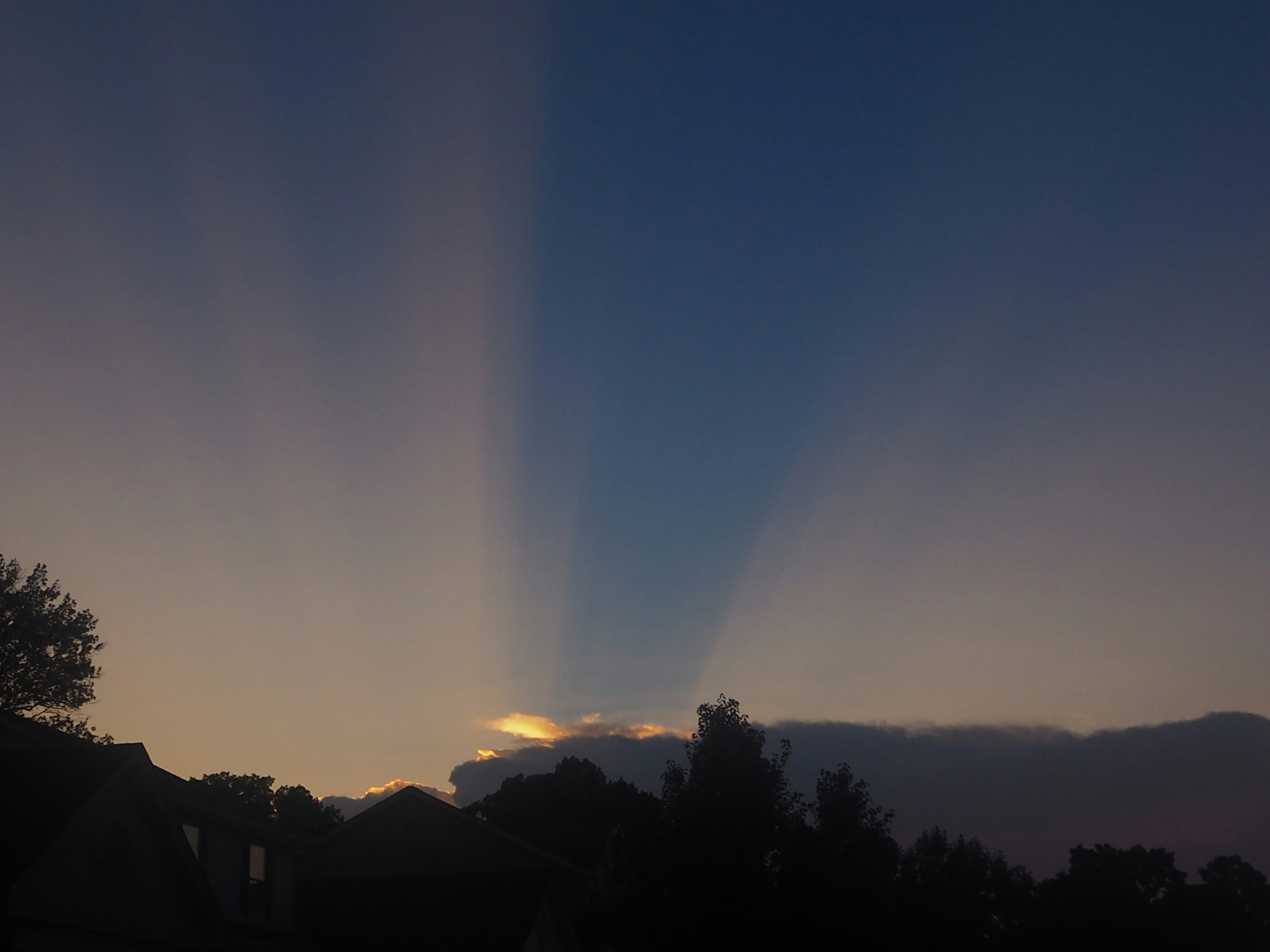 Dusk Beams Piercing the Quiet Horizon Over Suburban Silhouettes