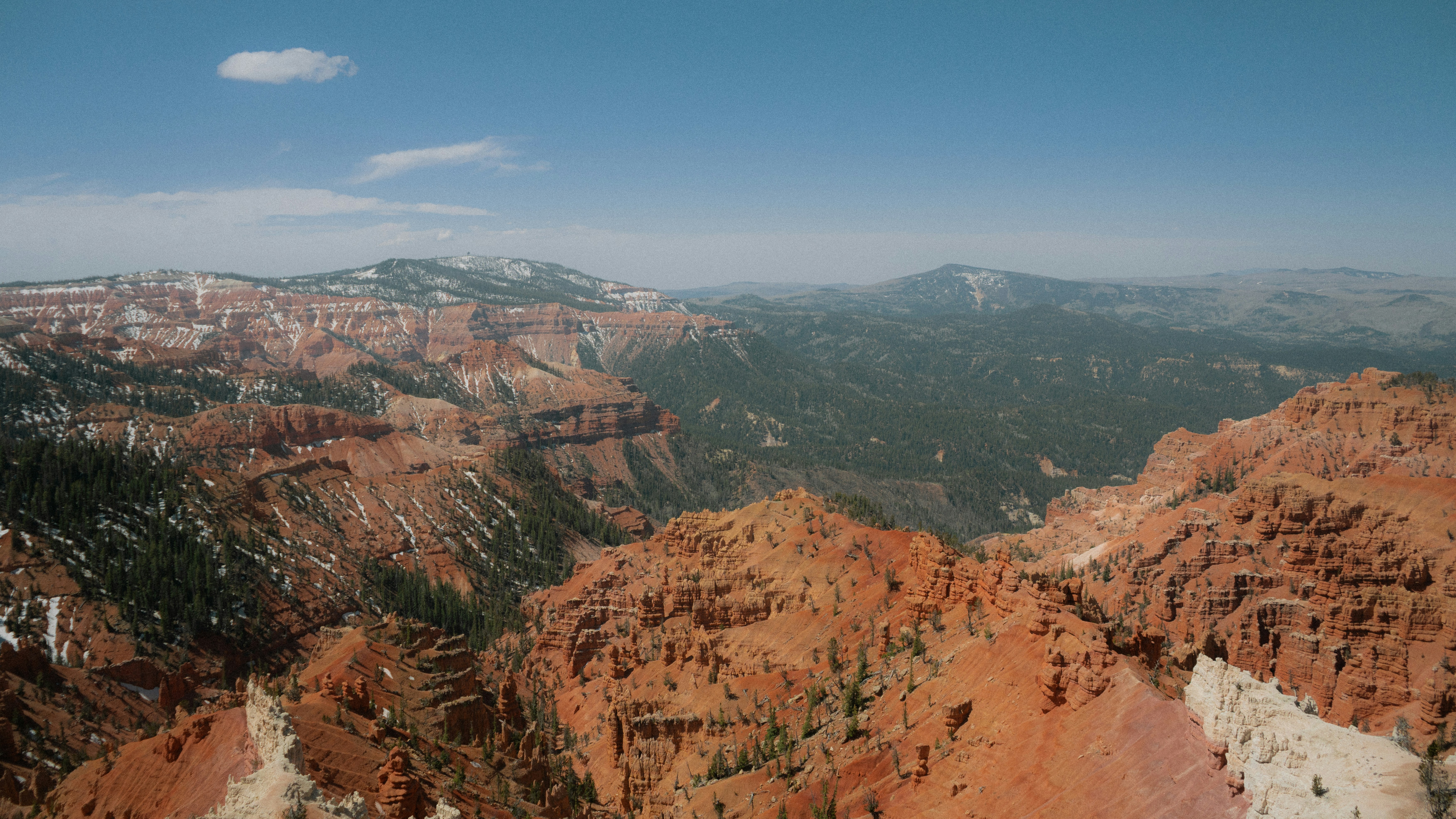 Des canyons de roches rouges s’étendent vers des montagnes lointaines ...