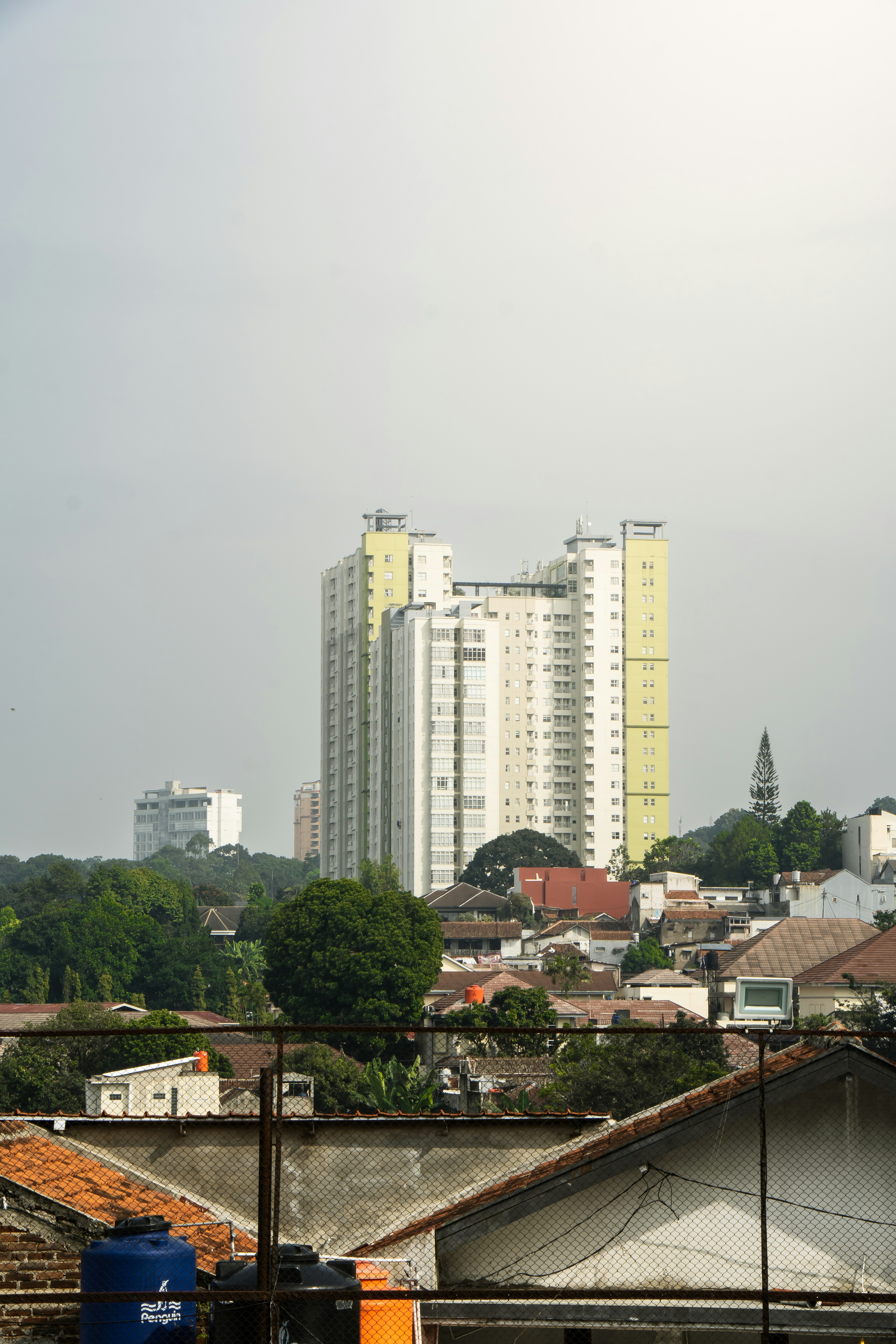 Modern high-rise buildings rise above a diverse urban landscape, showcasing a blend of architecture and greenery. The scene captures the essence of city life interwoven with nature.