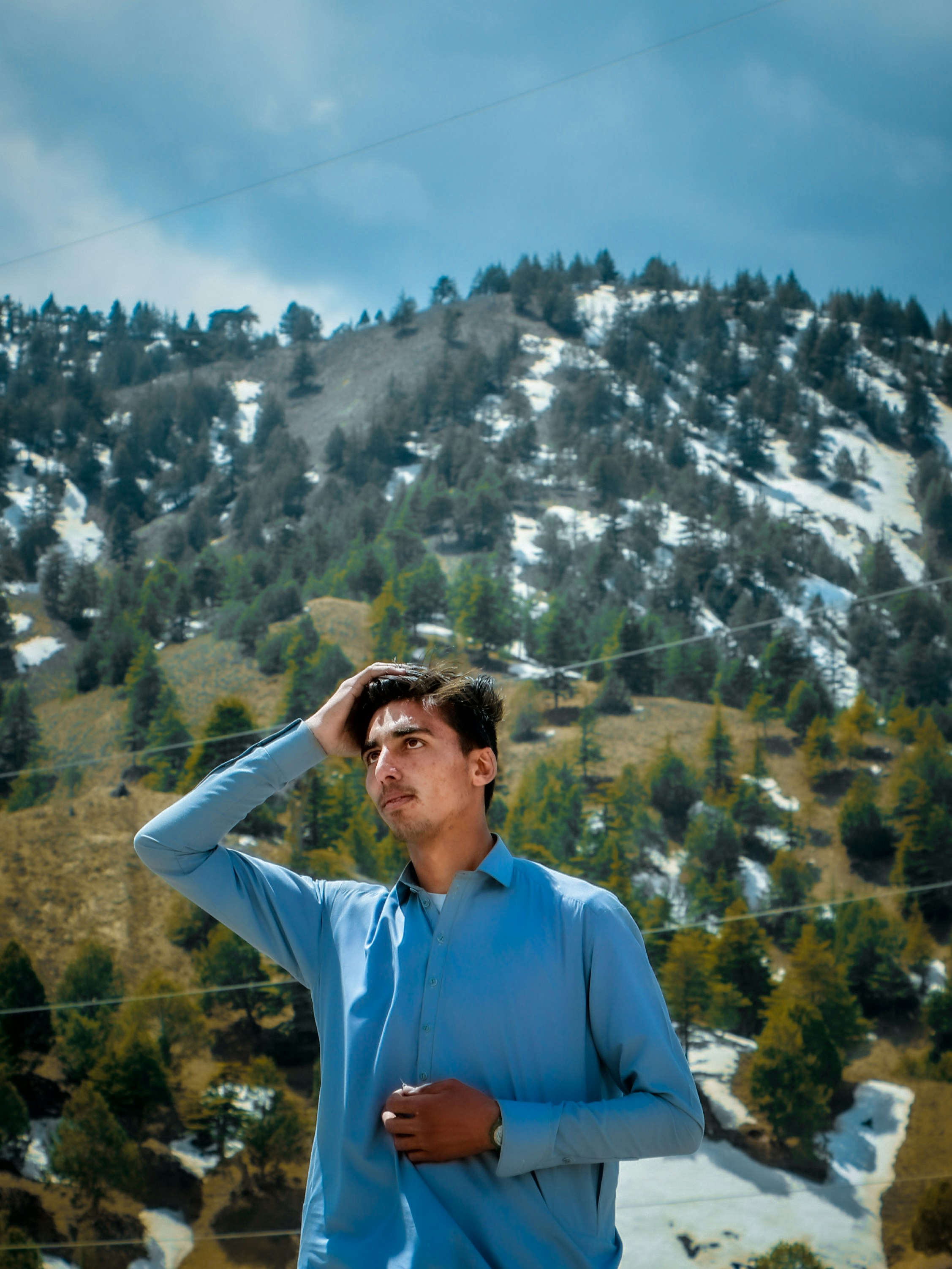 Blue Shirt Amid Snow-Kissed Peaks: Portrait at the Alpine Edge