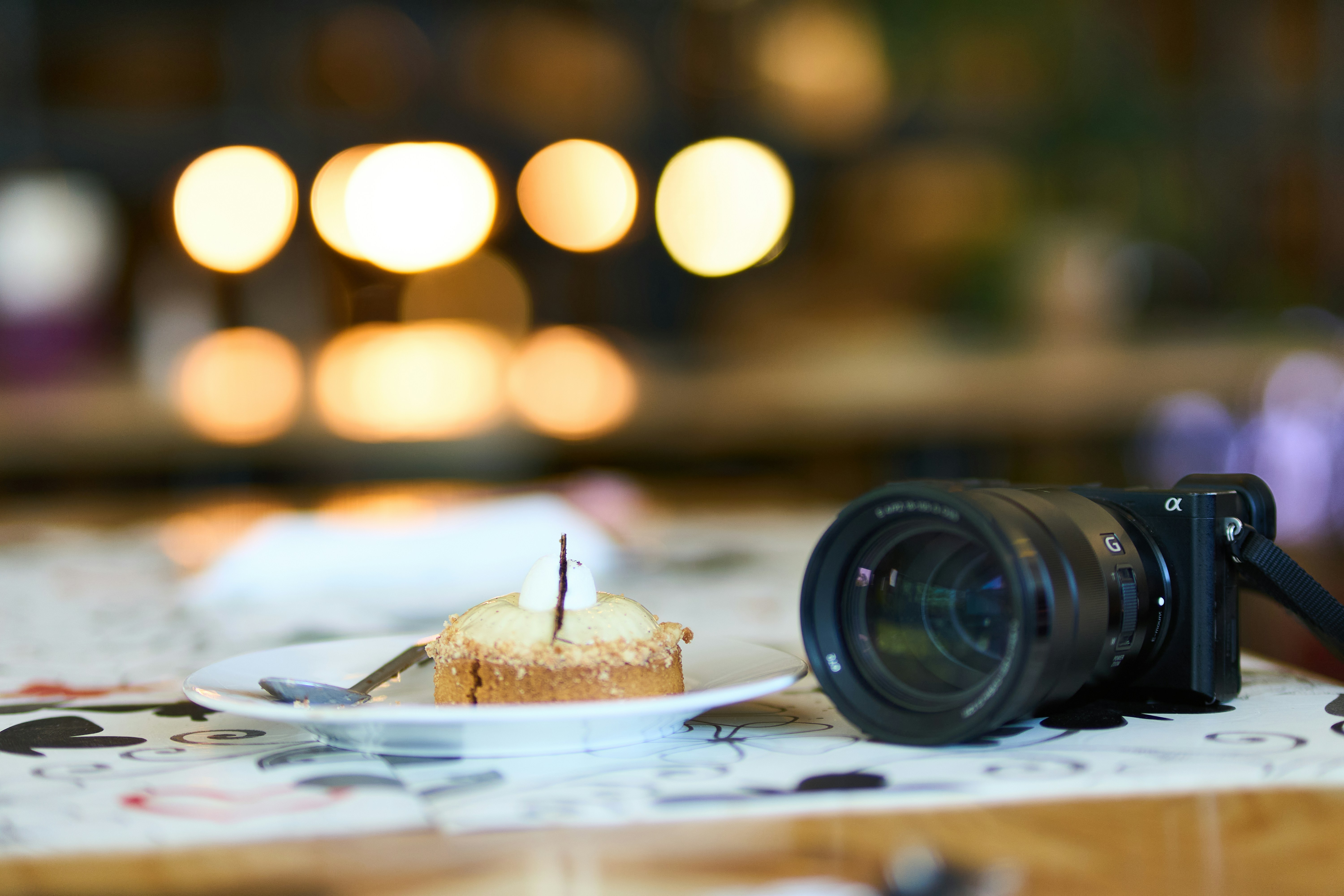 Close-Up Calm: A Candlelit Pastry Beside a Sony Alpha 7 II
