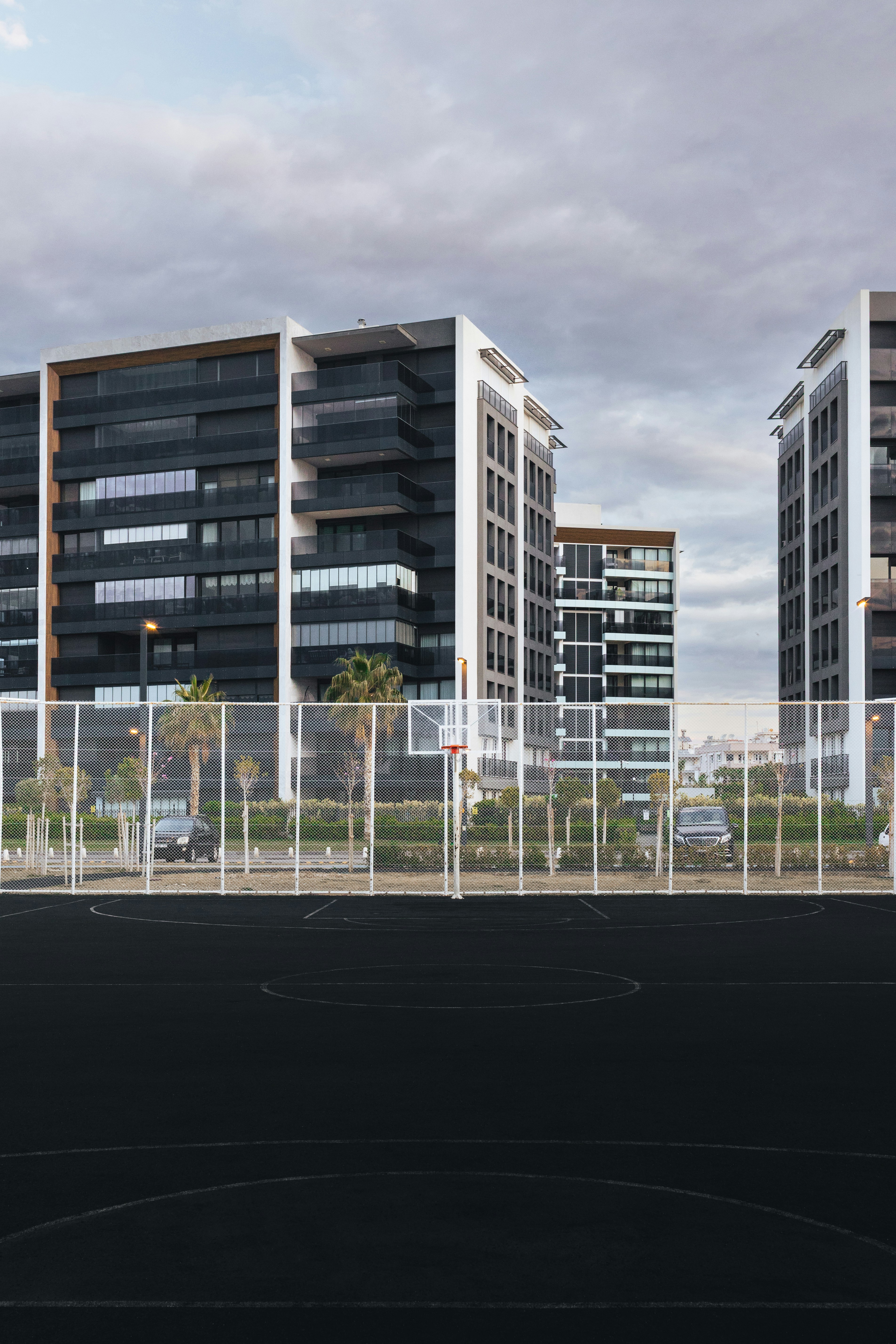 A modern basketball court framed by sleek, contemporary buildings, showcasing a blend of urban design and recreational space.