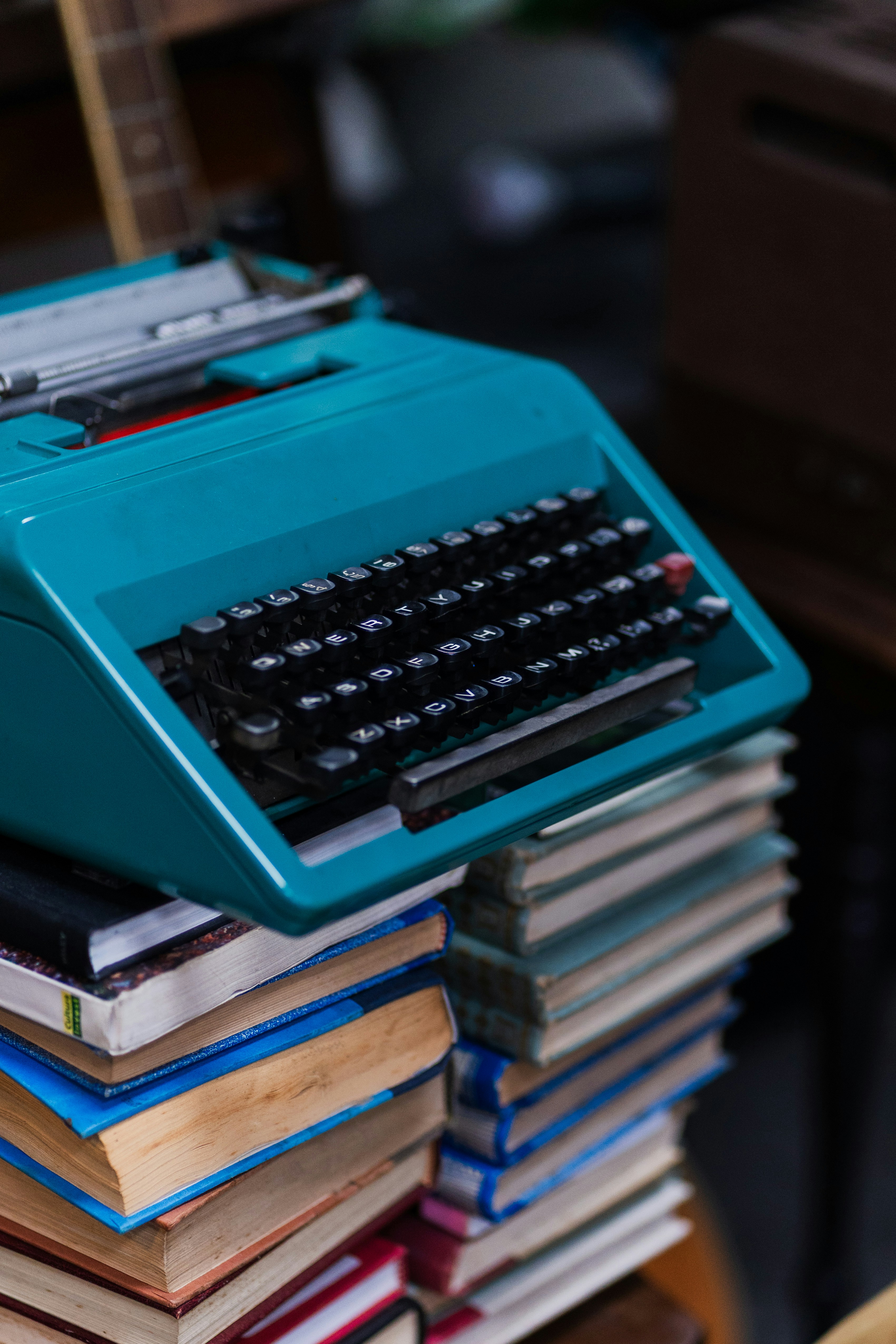 Teal Typewriter Reigning Over a Stack of Books