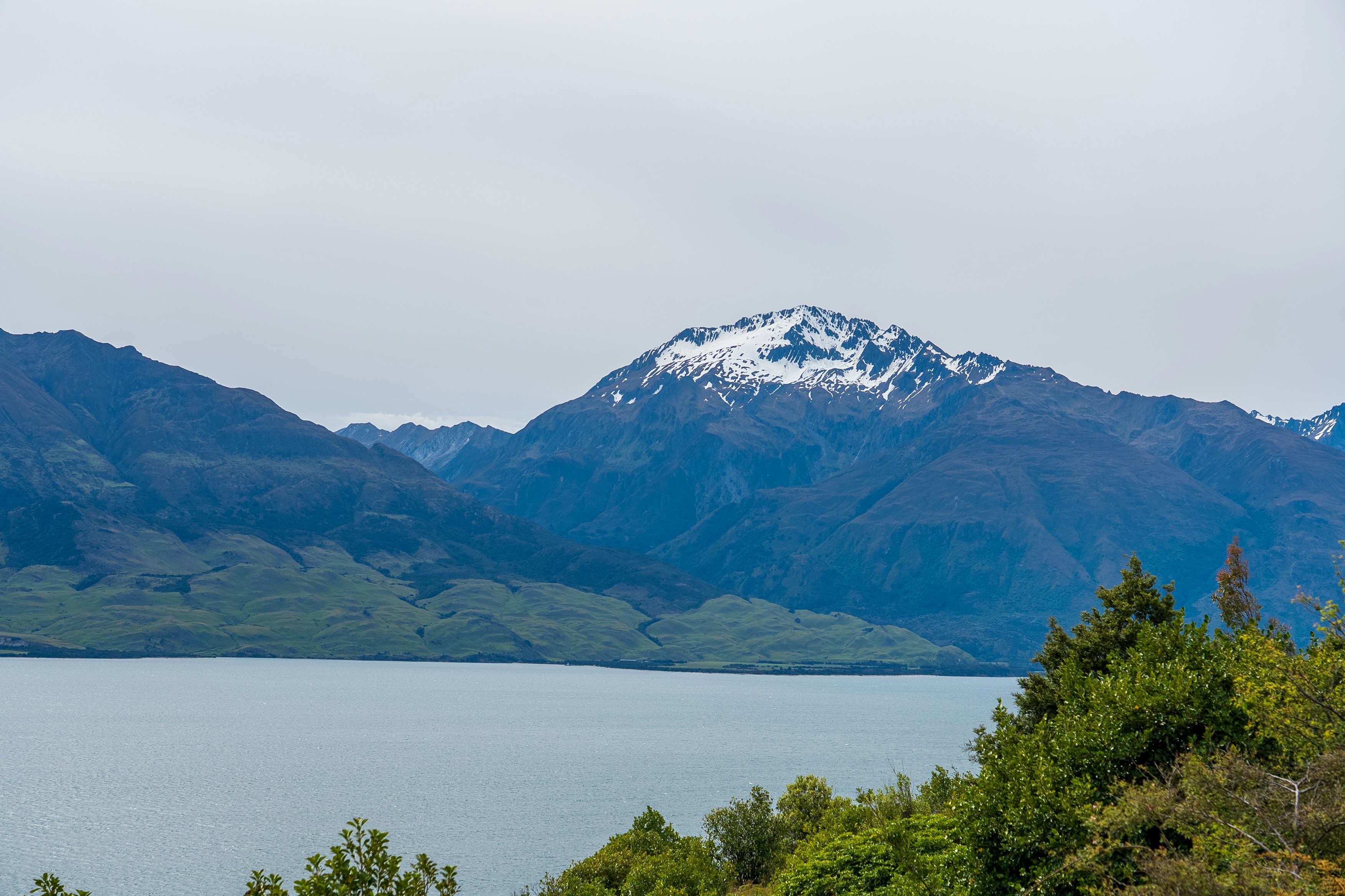 Mountains overlook a calm lake under a cloudy sky.