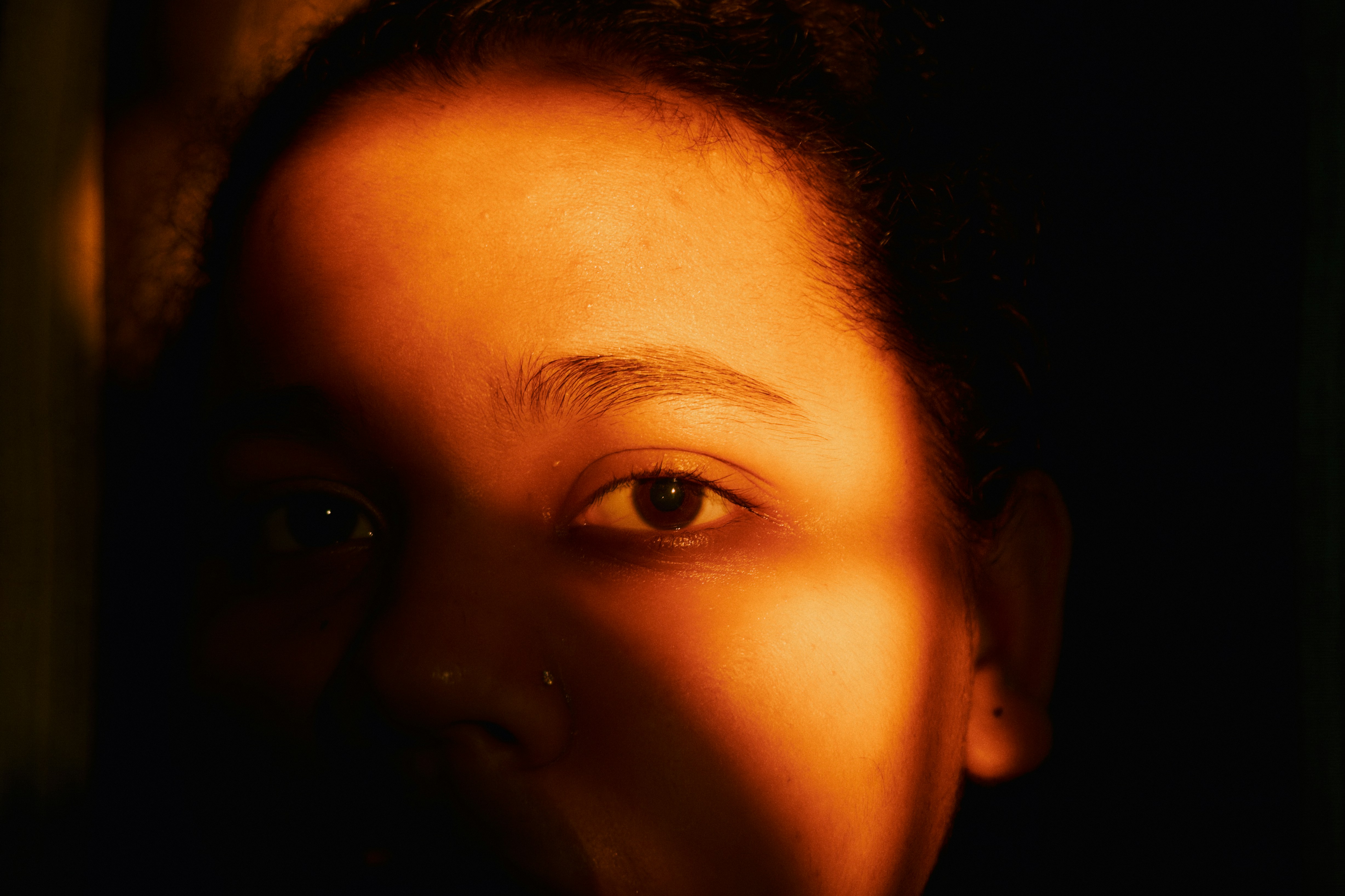 La iluminación cálida ilumina el rostro de una persona en la oscuridad ...