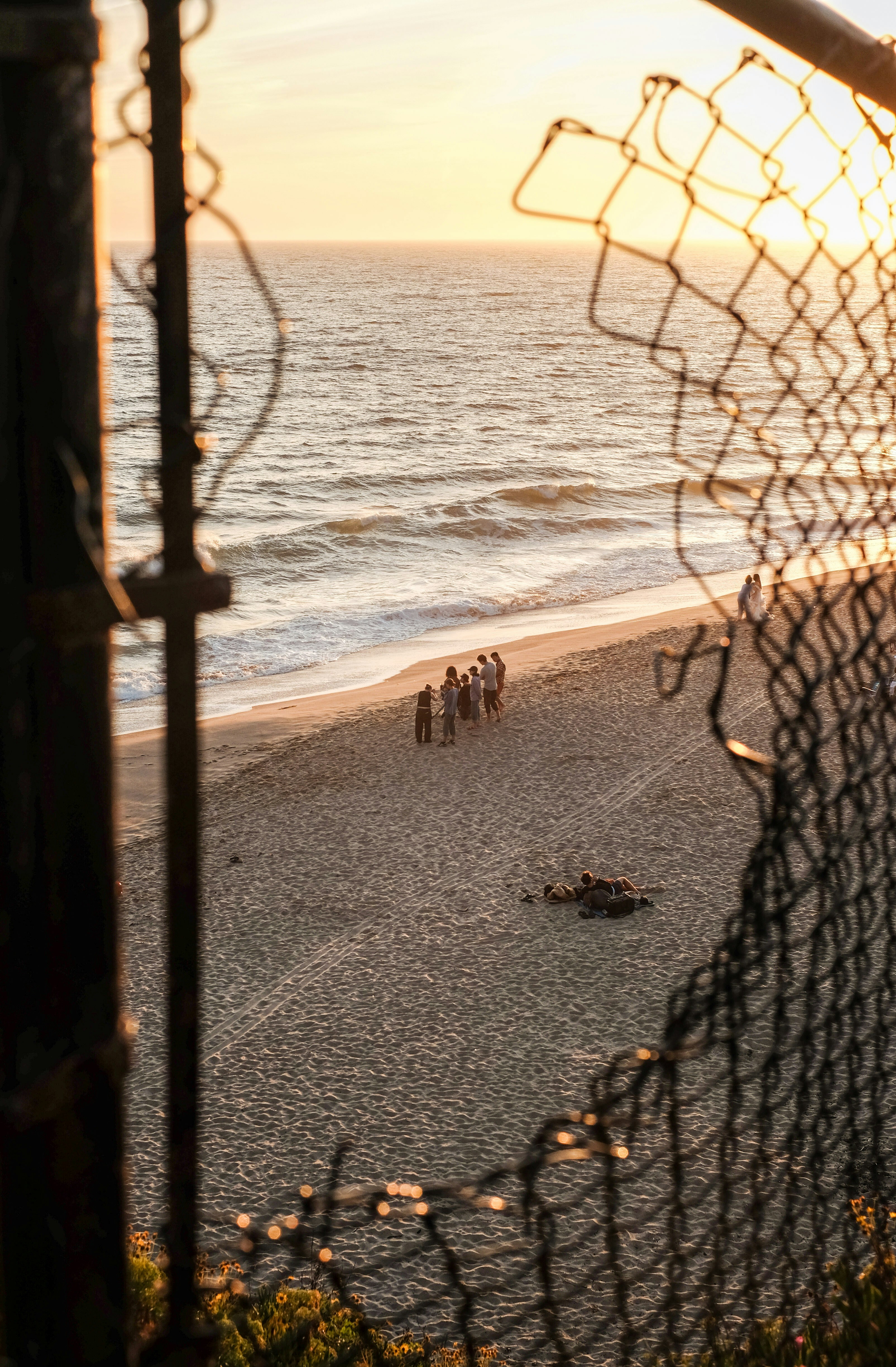 People gather at the beach during a sunset.