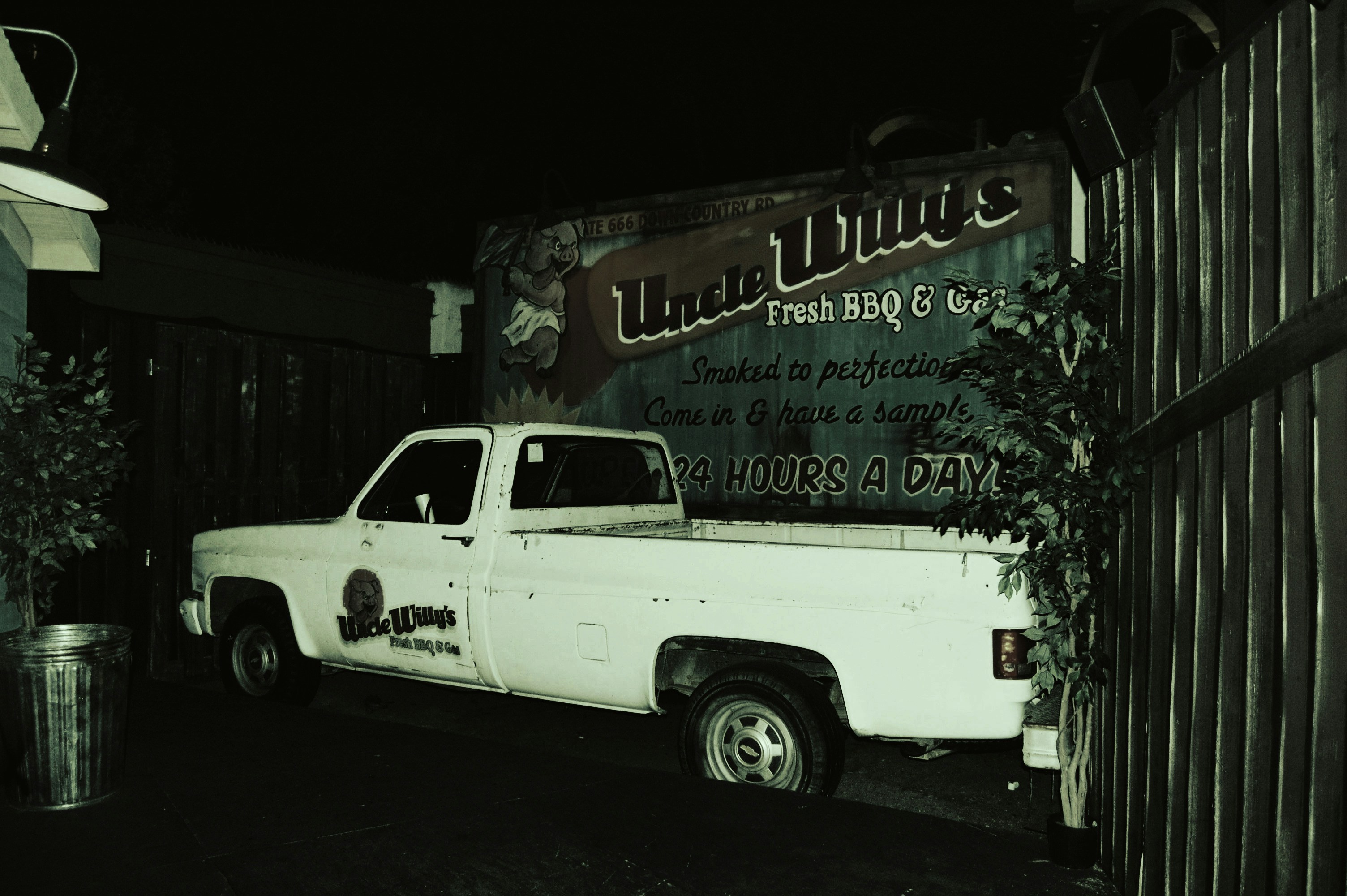 A white pickup truck sits near a restaurant sign.
