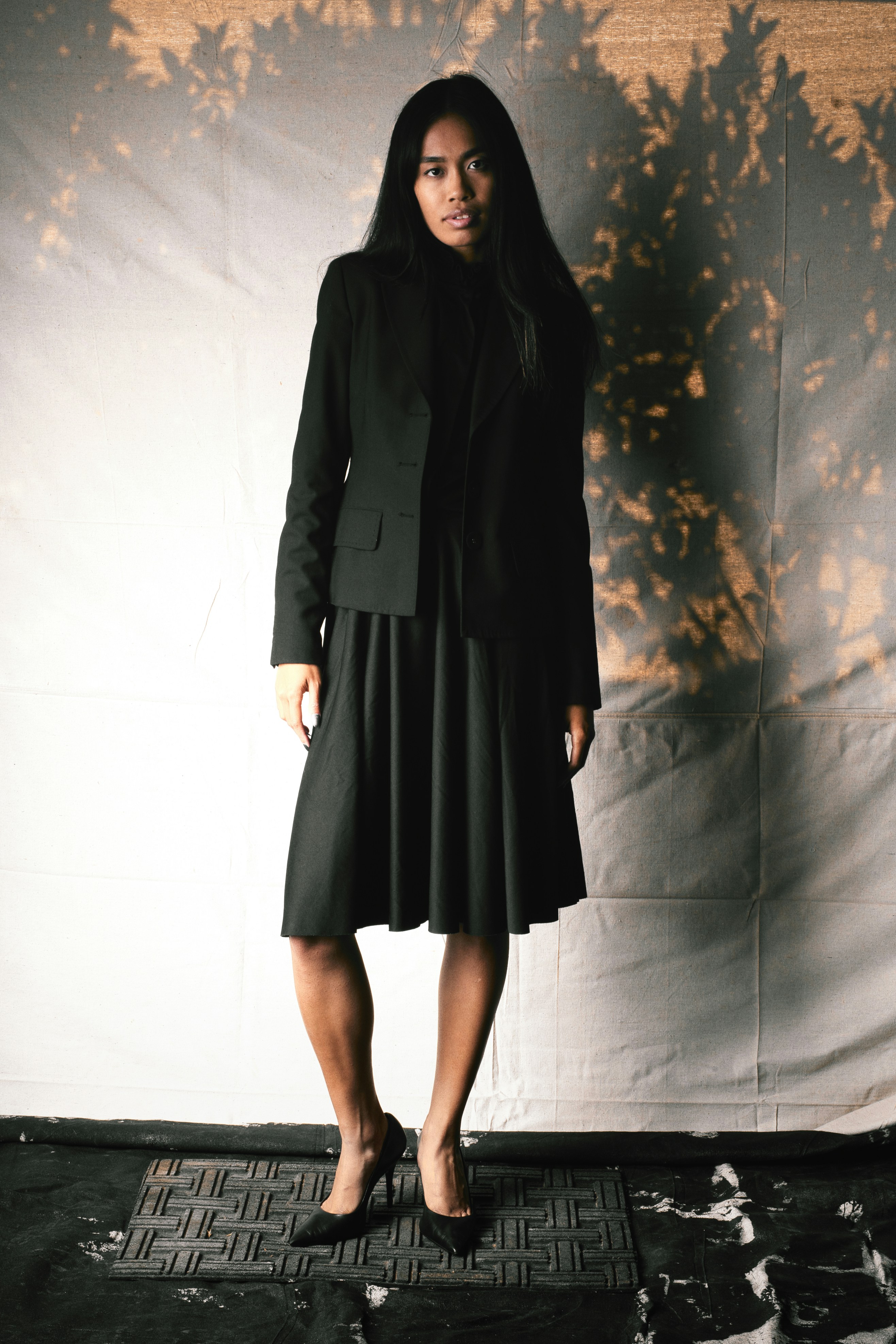 @izzieoooo | A woman stands in a black dress and jacket.