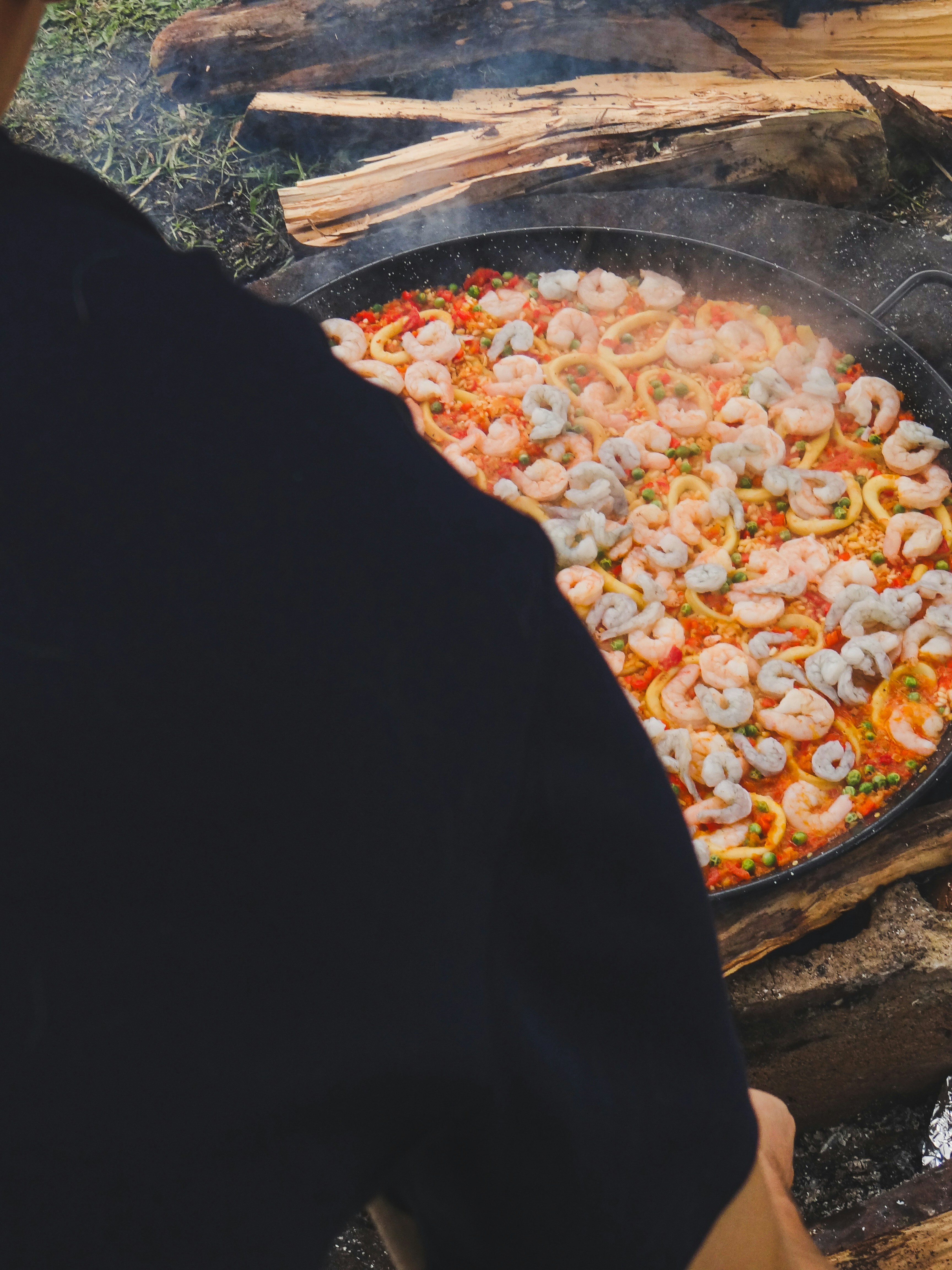 Seafood Spanish Paella with shrimp, clams and squid | Cooking seafood paella outdoors on a wood fire.