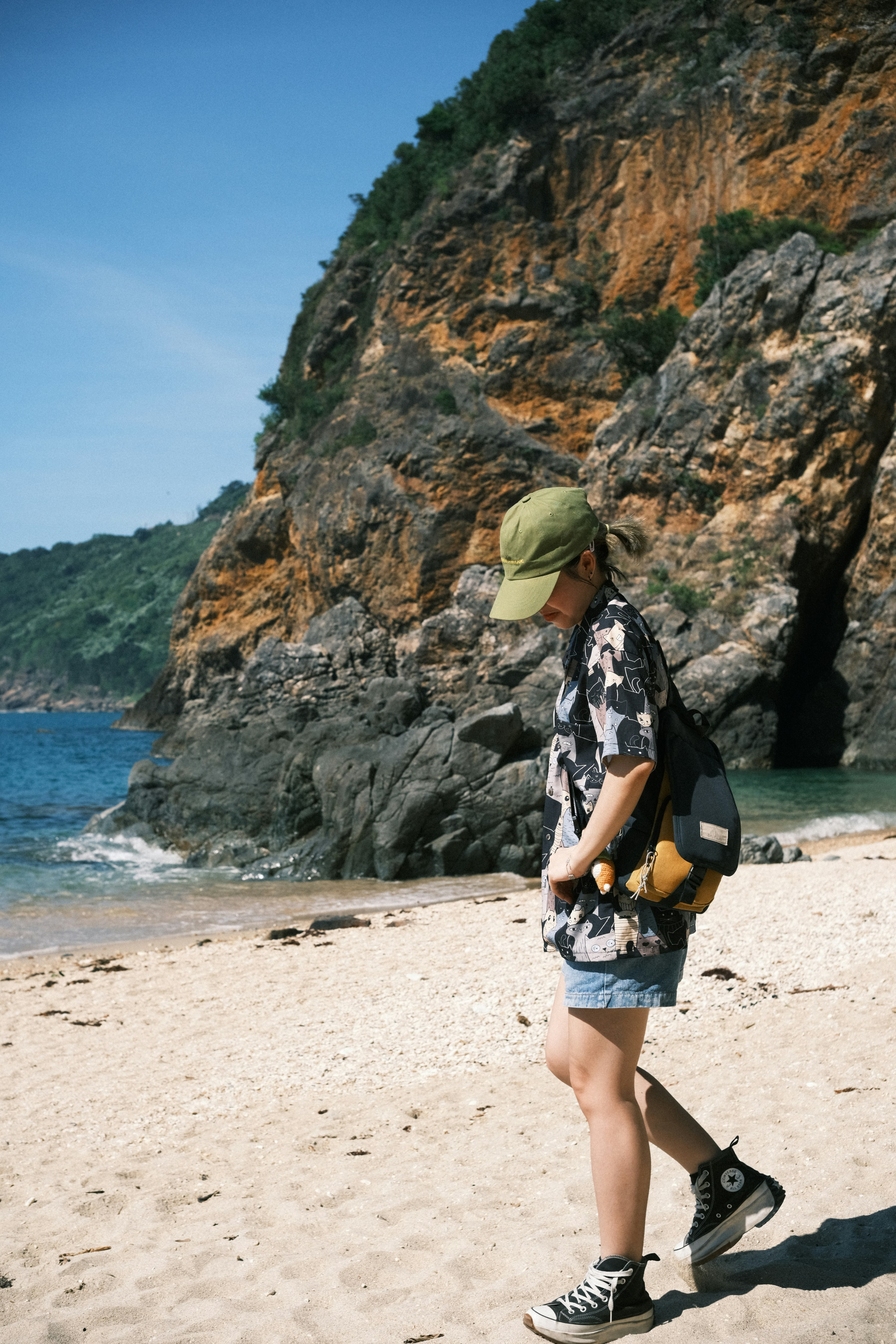 Woman walks on a sandy beach next to cliffs. photo – Free Image on Unsplash