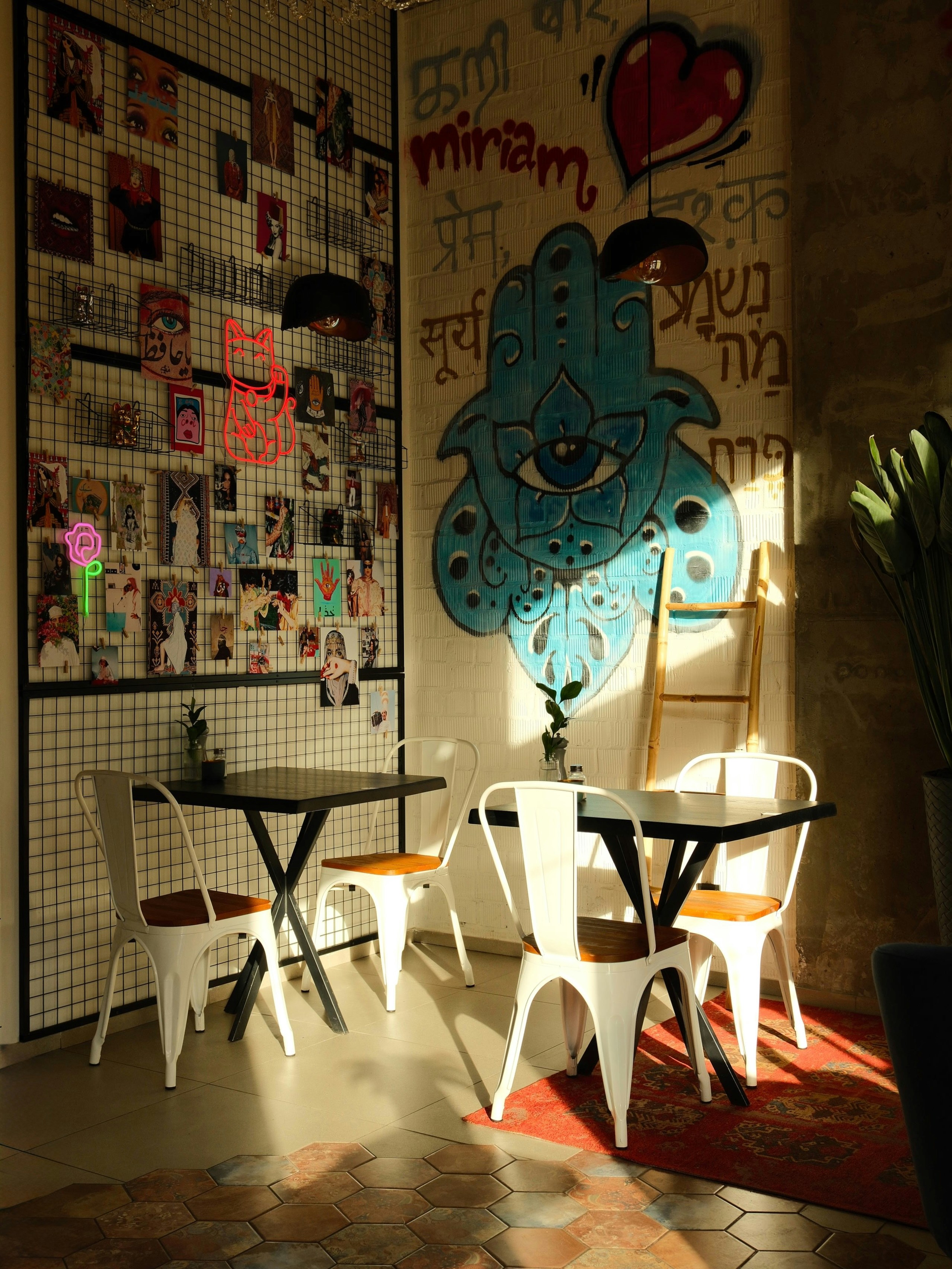 Cozy urban café corner with modern white chairs, bold wall art, and warm natural sunlight. Perfect blend of street-style creativity and relaxed atmosphere. | A stylish restaurant's interior, ready for customers.
