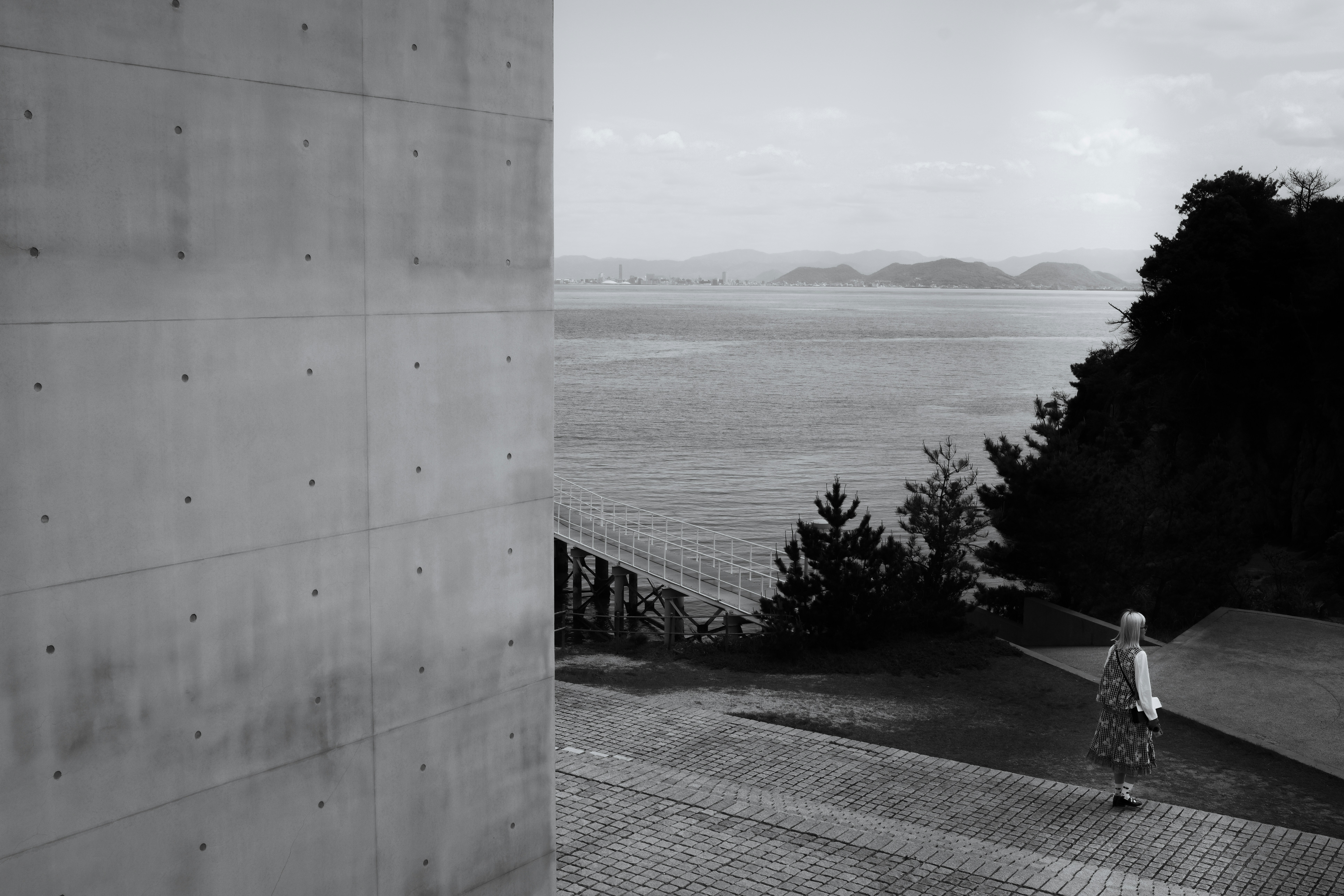 Lone Figure at the Concrete Seafront: Monochrome Geometry by the Sea