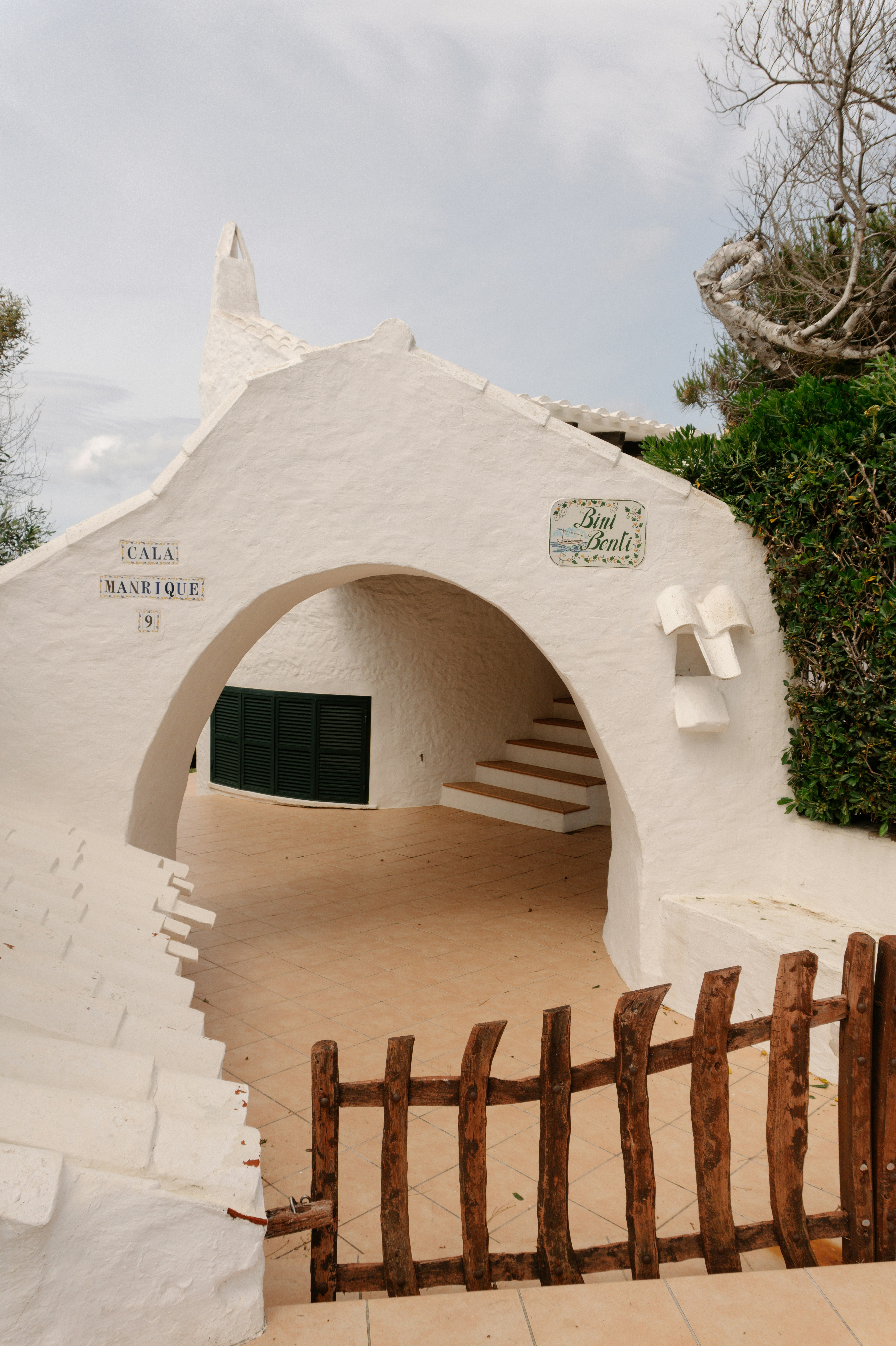 A white, arched building with stairs and a fence.