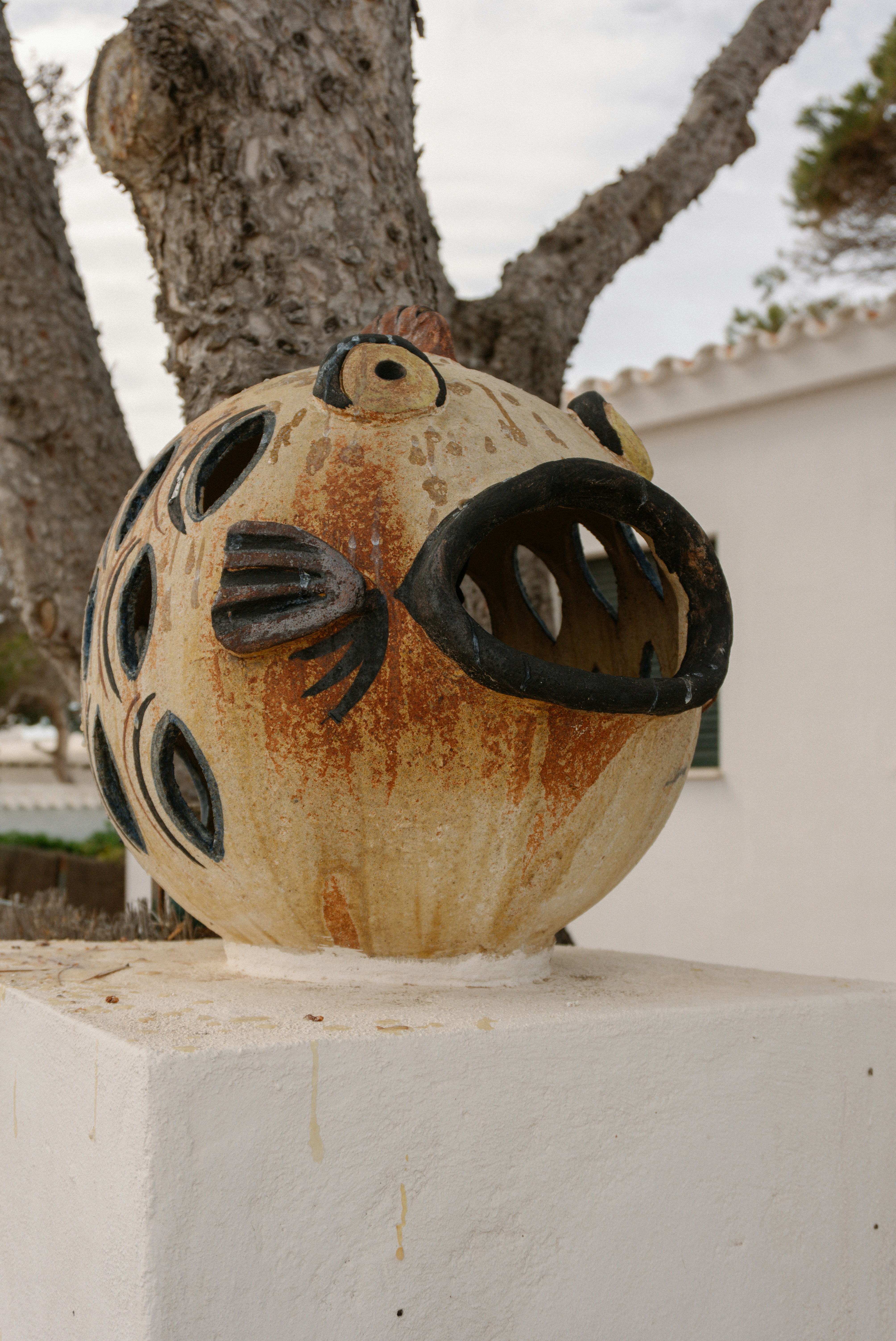 Clay Facade Gourd: A Whimsical Ceramic Head of Fire Held by a Tree.