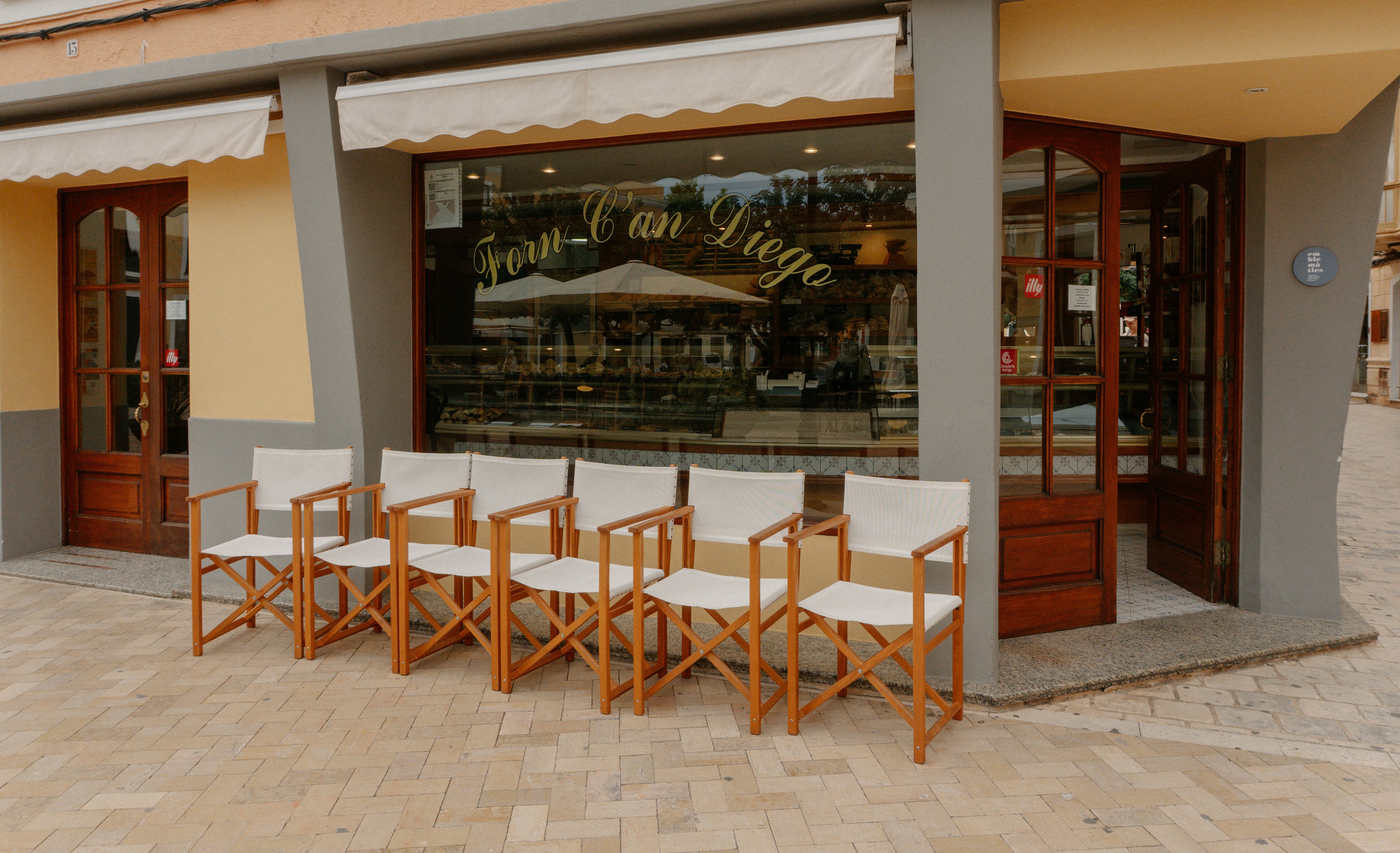 A bakery shop with chairs is shown outside. photo – Free Interior ...