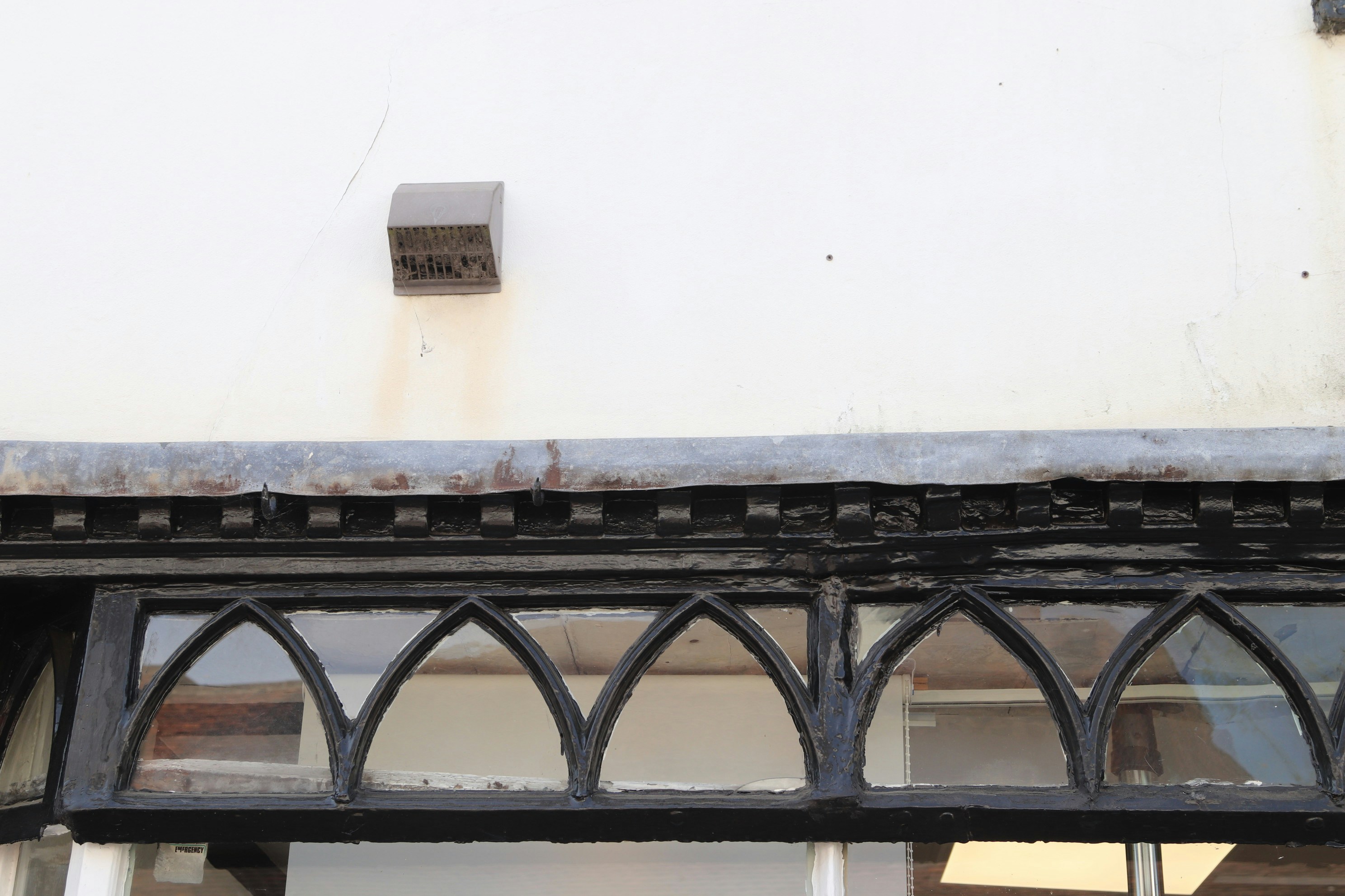 Ironwork Arches Over a Quiet Shopfront Beneath a Stark White Facade
