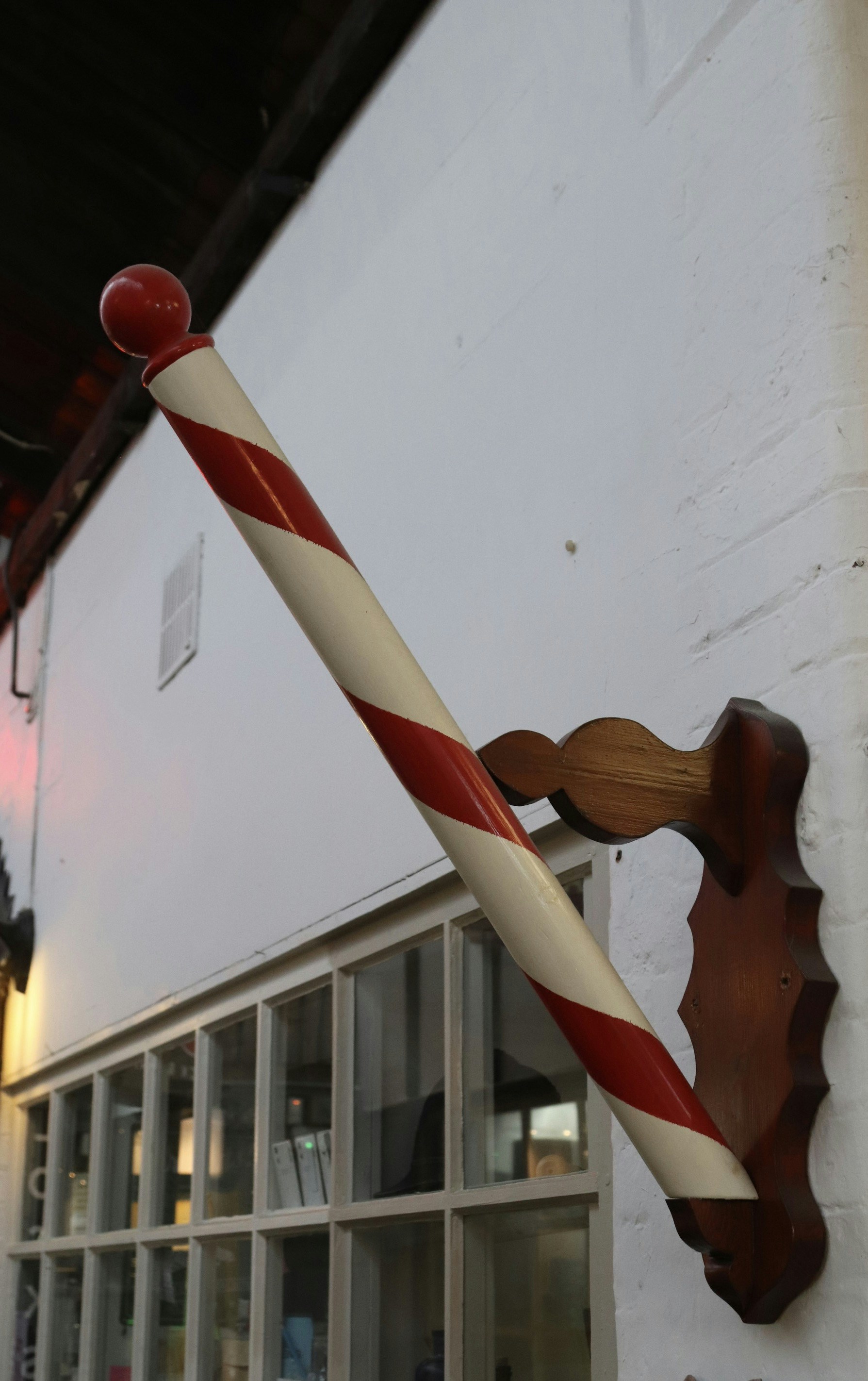 A Diagonal Barber Pole Brings Red-and-Cream Rhythm to a Quiet Facade