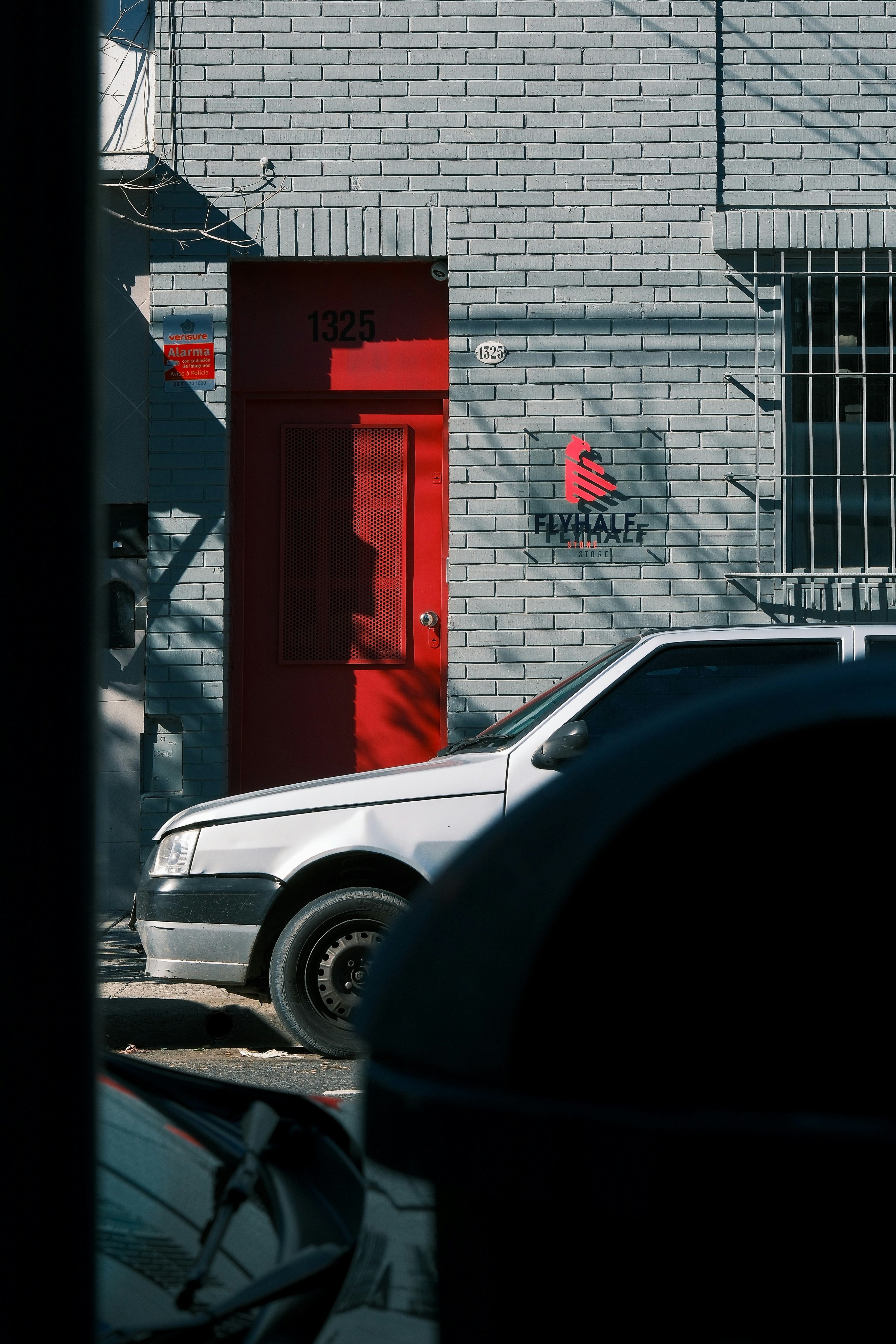 1325 Red Door Framed by Shadow on a Gray Brick Street
