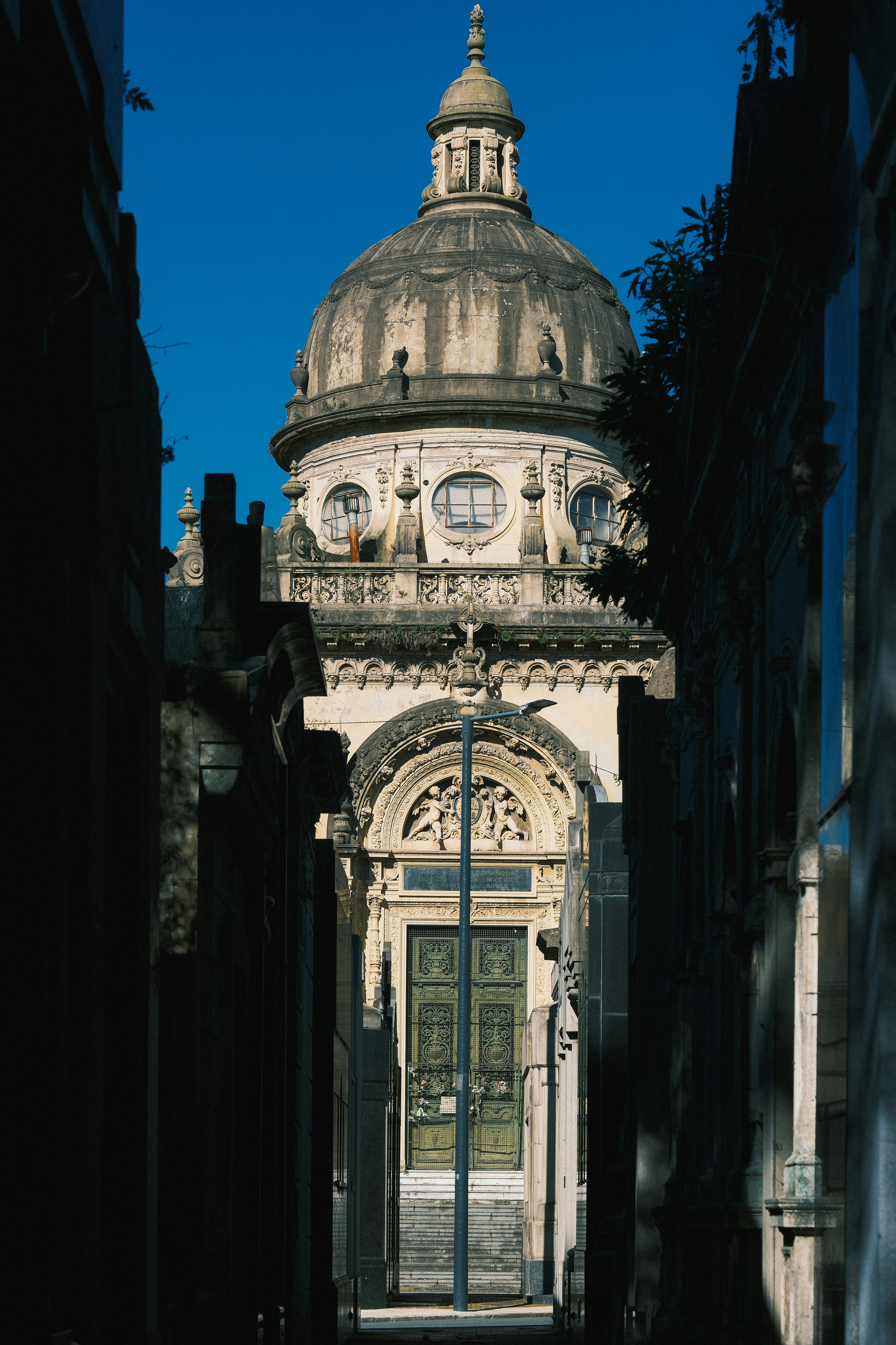 Intricate dome and ornate doorway framed by narrow alleyway, showcasing historical architecture against a clear blue sky.