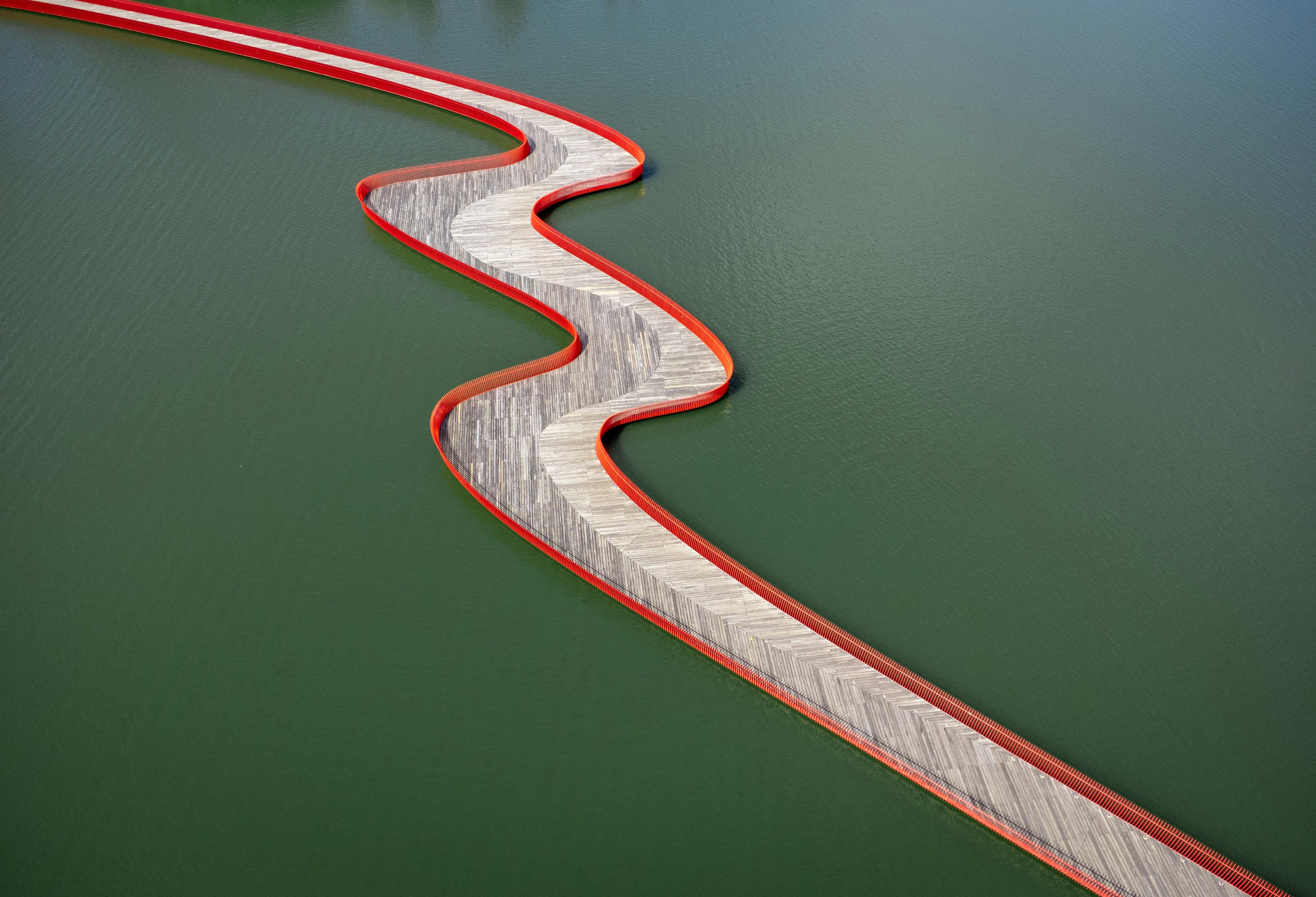 A winding bridge curves over the water. photo – Free Structure Image on ...