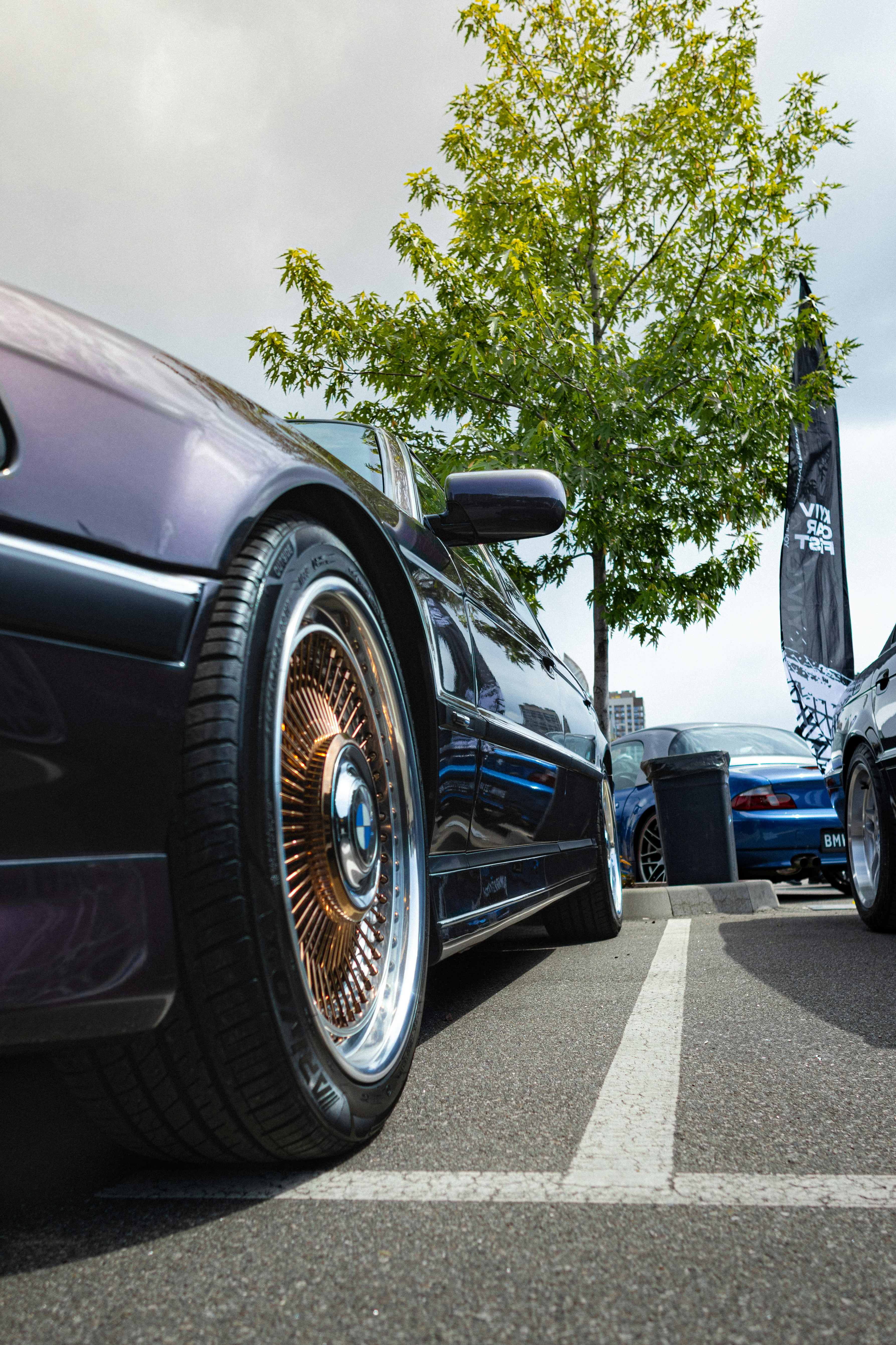 Copper Spokes in the Spotlight: A Low-Angle Car Show Moment