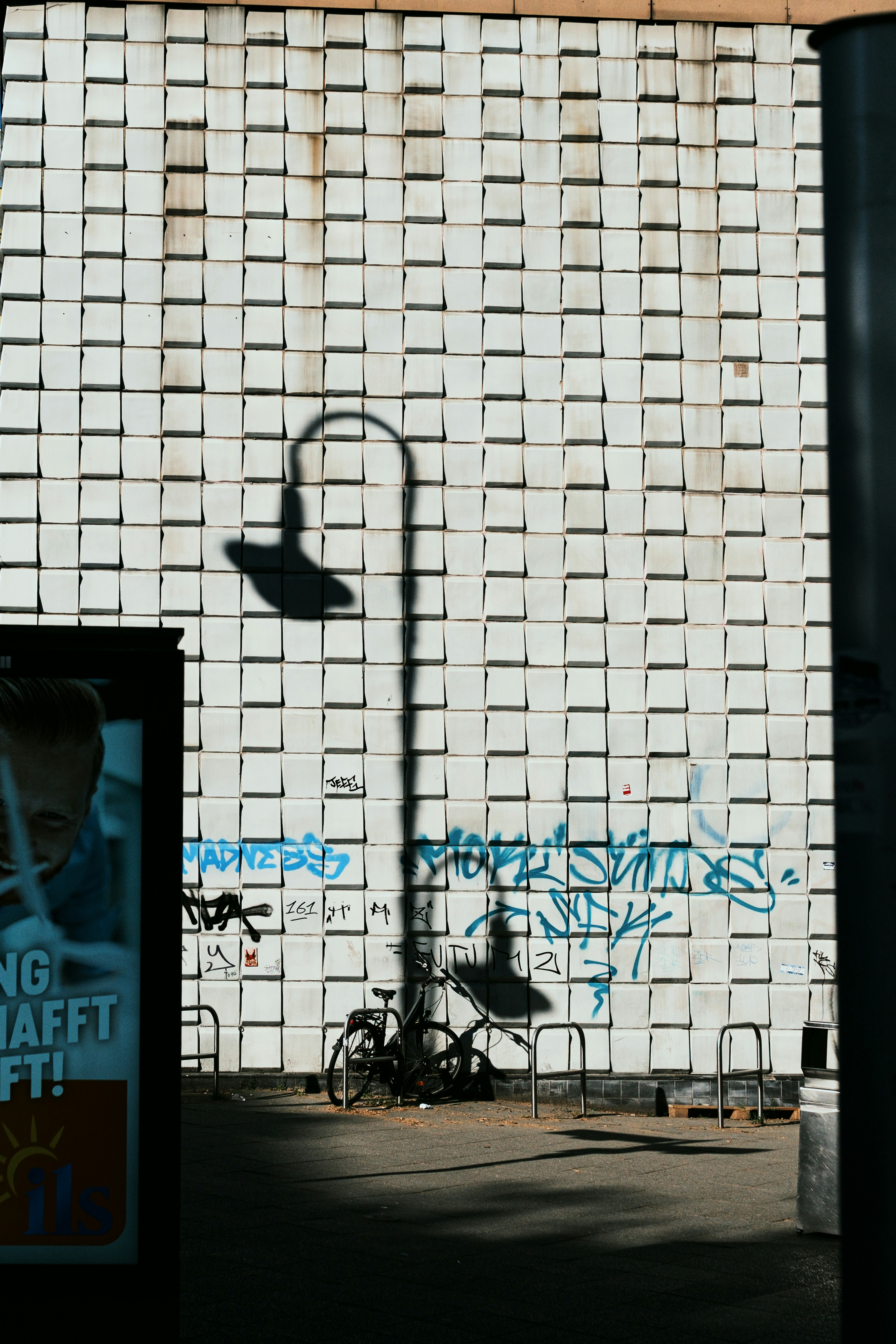 Urban Shadow: A Streetlamp Casts Its Shape Across a Graffiti-Waced Wall