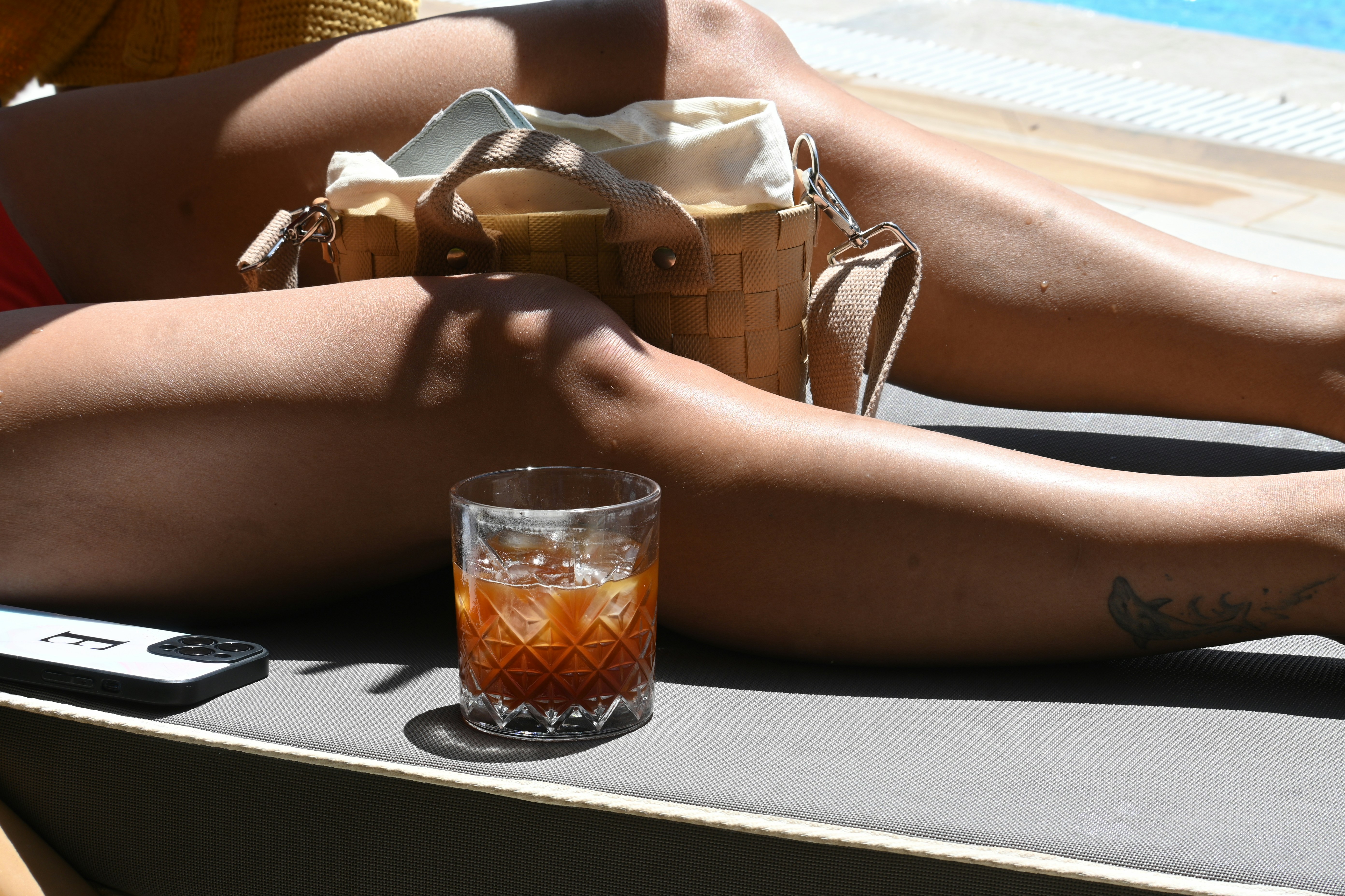 Sunlit Terrace: Relaxed Legs, Ice-Drink, and a Straw Bag