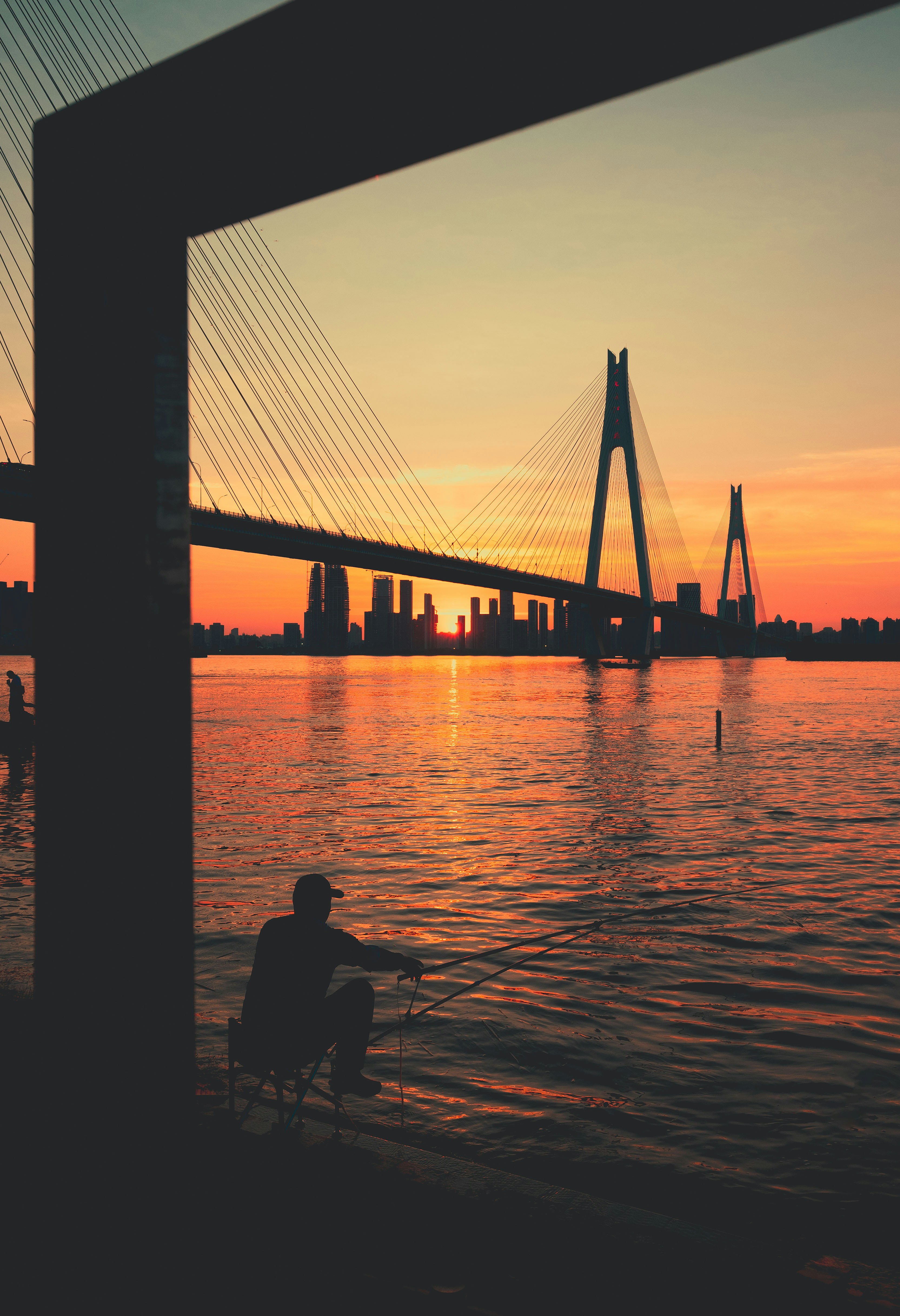 Dusk Over the River: A Cable-Stayed Bridge Framing a Lone Angler