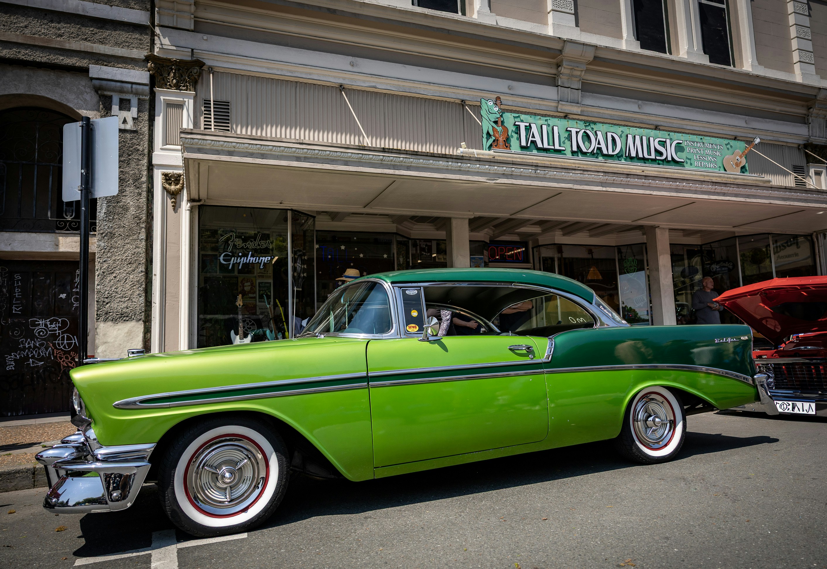 This beautifully restored two-tone green Chevy Bel Air sits in front of a vintage music shop in downtown Petaluma during the American Graffiti car show. Classic style and color in perfect harmony.