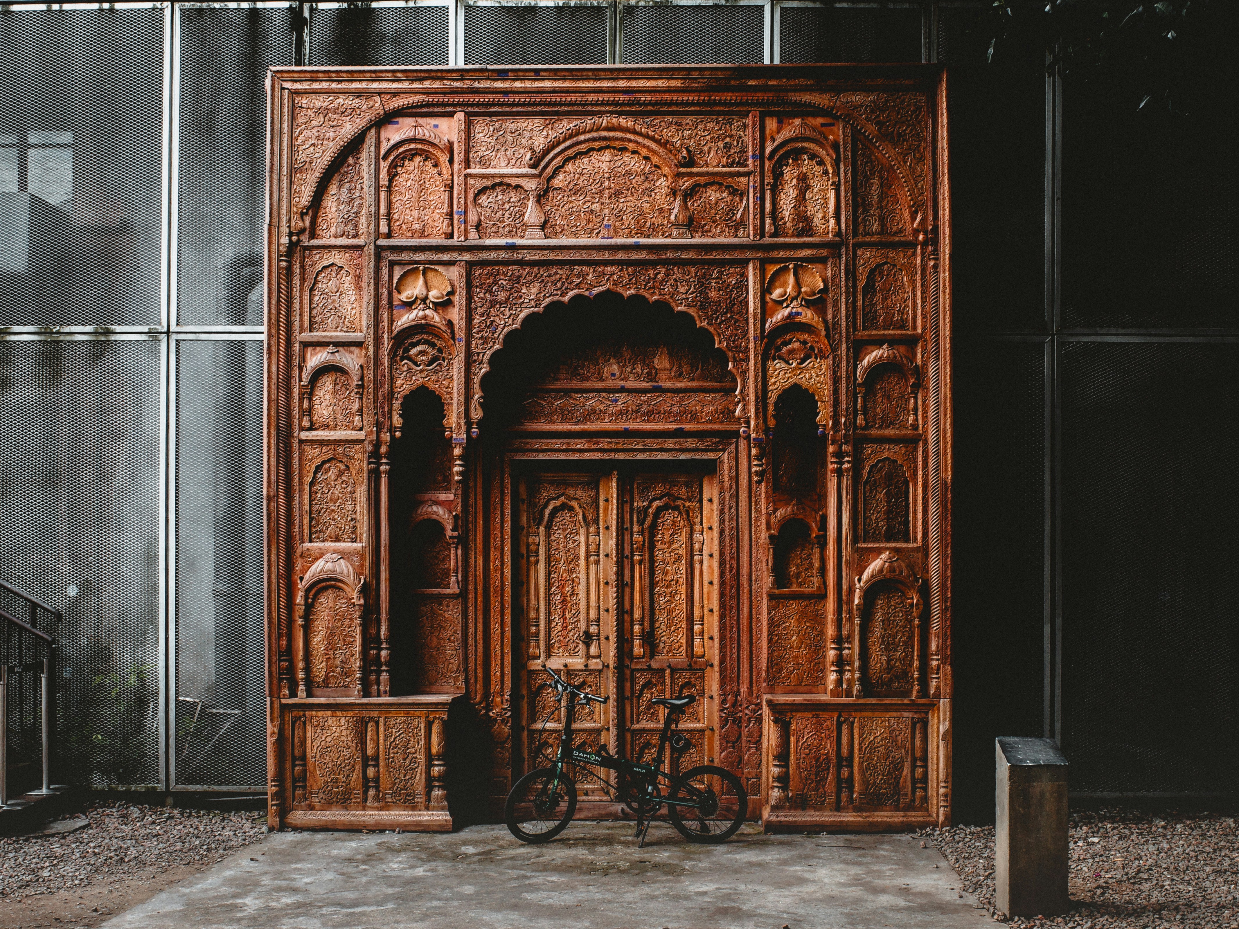 Carved Archway Gate with a Bicycle: A rust-toned doorway in shadow