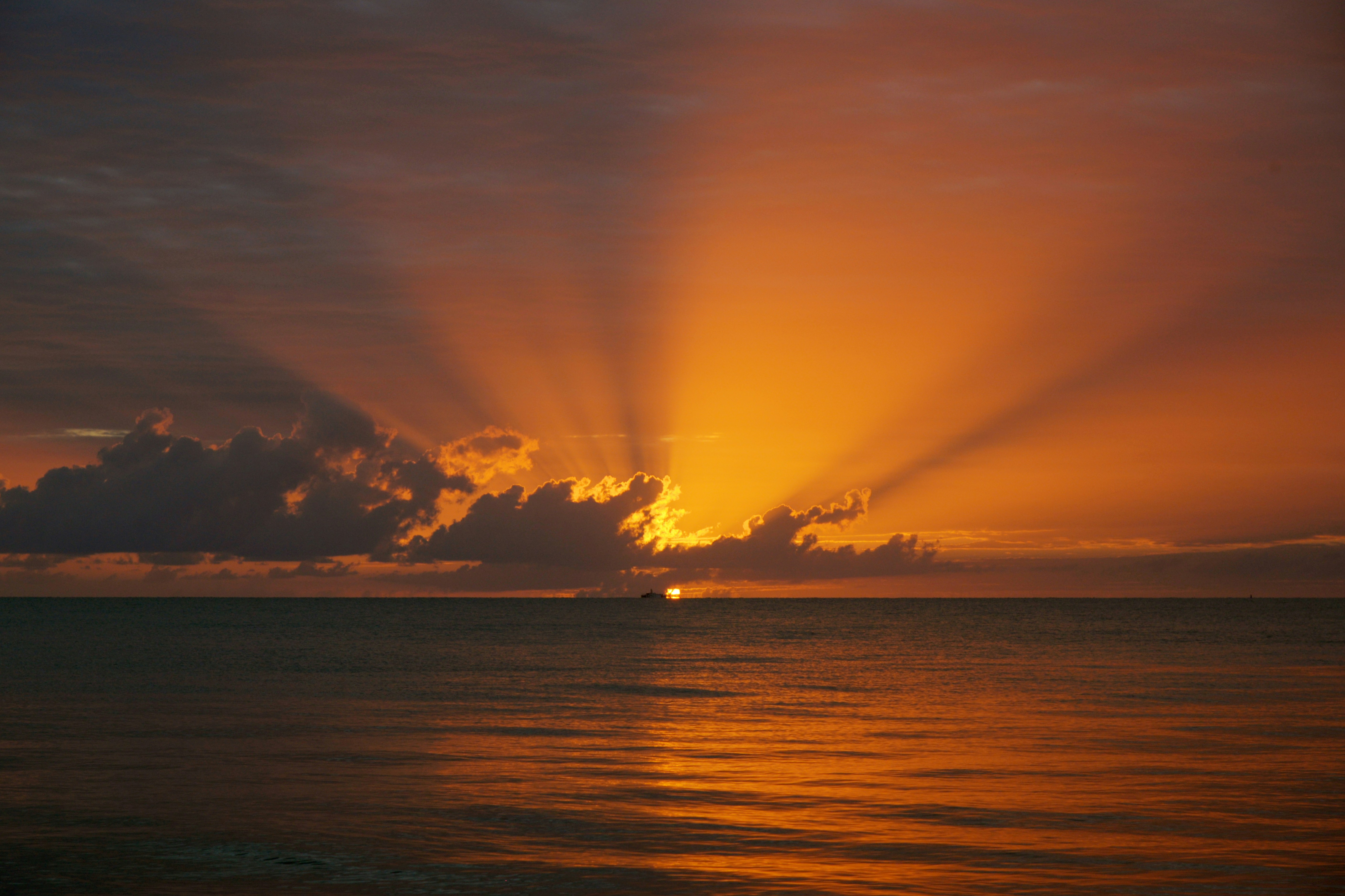 Gilded Horizon: Sunbeams Unfurl Across a Quiet Sea at Dusk